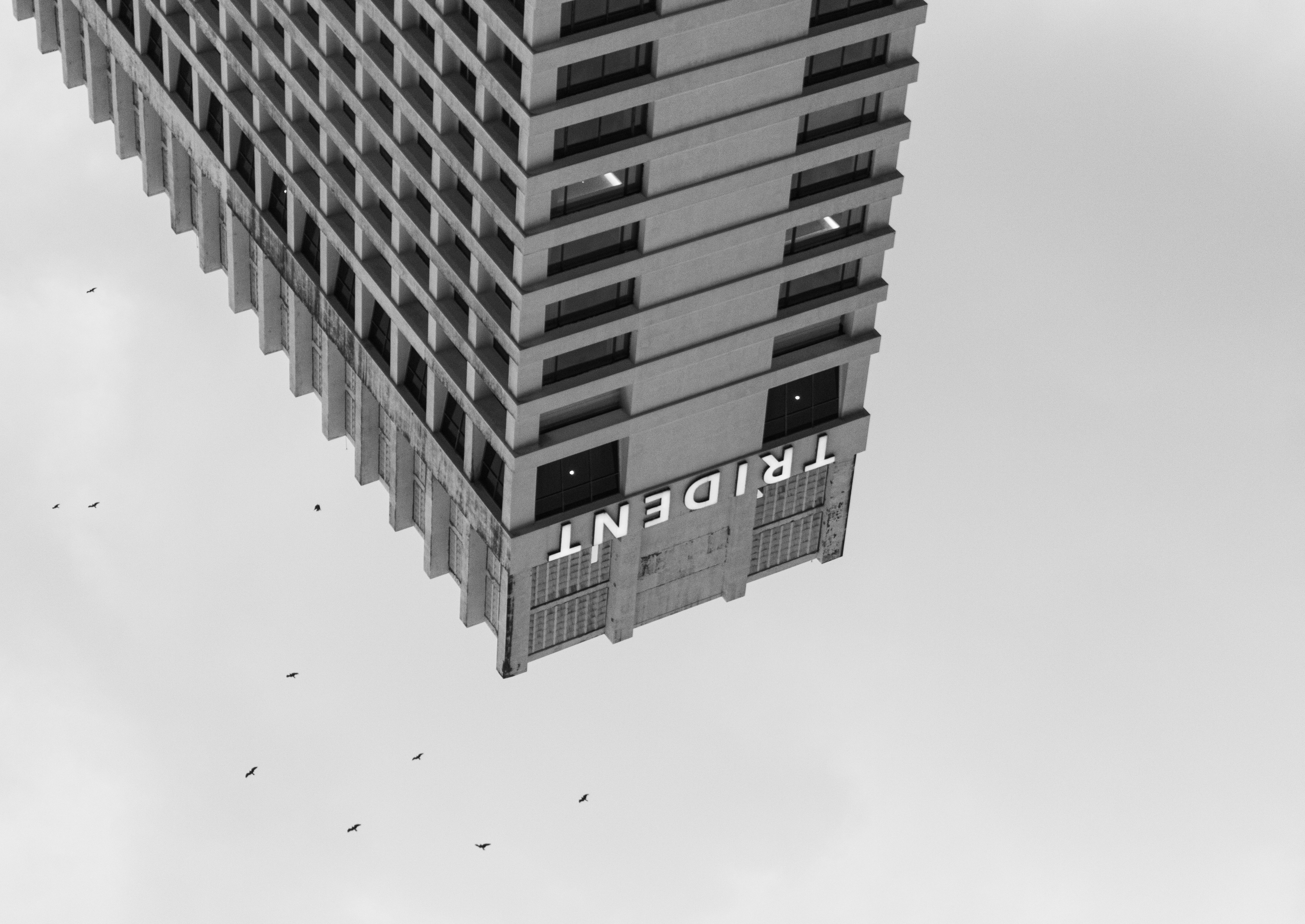 The falling building. An experimental black and white photo clicked by me in Mumbai. | A tall building's reflected image against a clear sky.