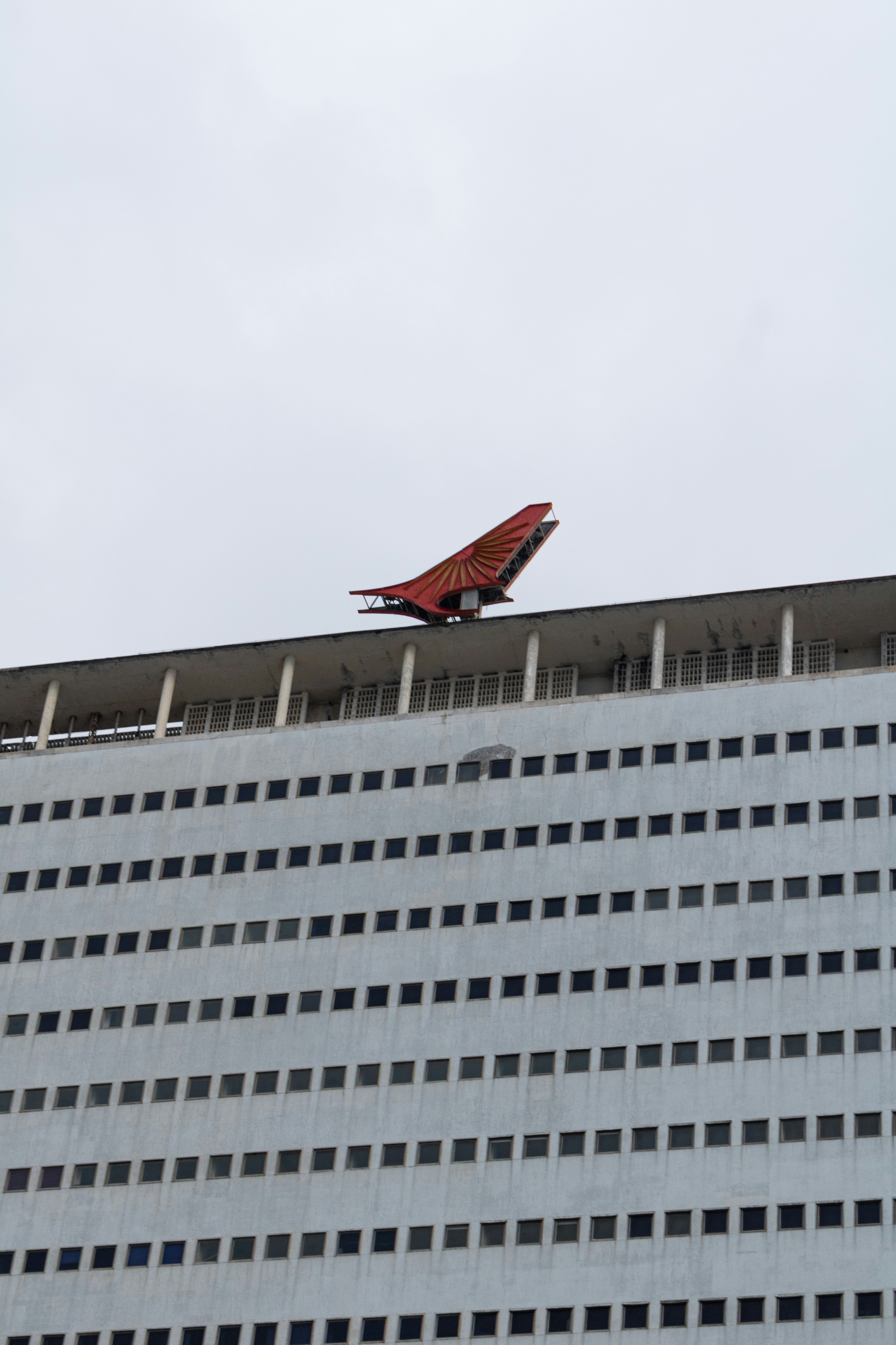 The Air India building, located in Mumbai's Nariman Point, is a prominent landmark with a rich history and unique architectural style. It was designed by John Burgee of the architectural firm Johnson/Burgee and completed in 1974. The building is known for its central air conditioning, one of the first in India to feature this, and for its escalators, which were also a novelty at the time. | Airplane tail on a high-rise building's roof.