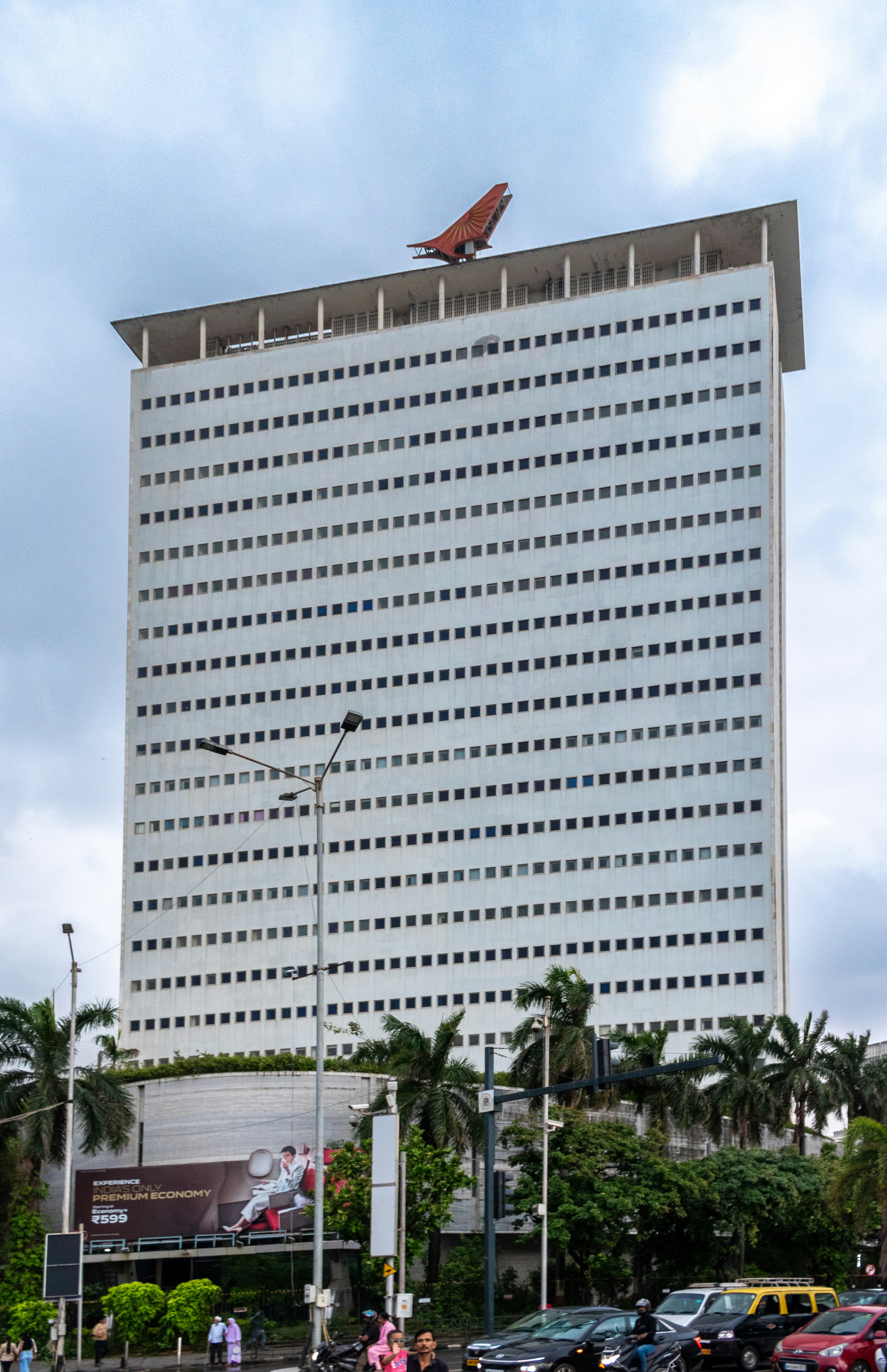 The Air India building, located in Mumbai's Nariman Point, is a prominent landmark with a rich history and unique architectural style. It was designed by John Burgee of the architectural firm Johnson/Burgee and completed in 1974. The building is known for its central air conditioning, one of the first in India to feature this, and for its escalators, which were also a novelty at the time. | A skyscraper with an aircraft on top.