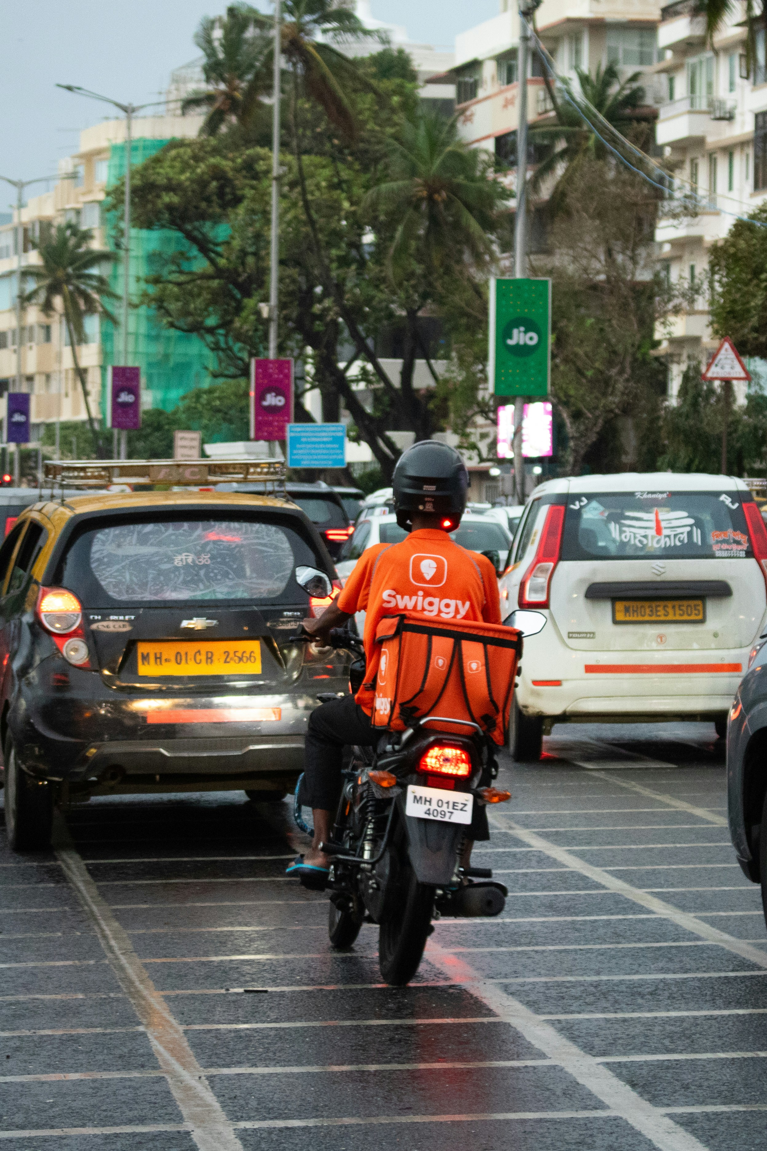 Swiggy delivery rider navigates traffic on a motorcycle. photo – Free ...