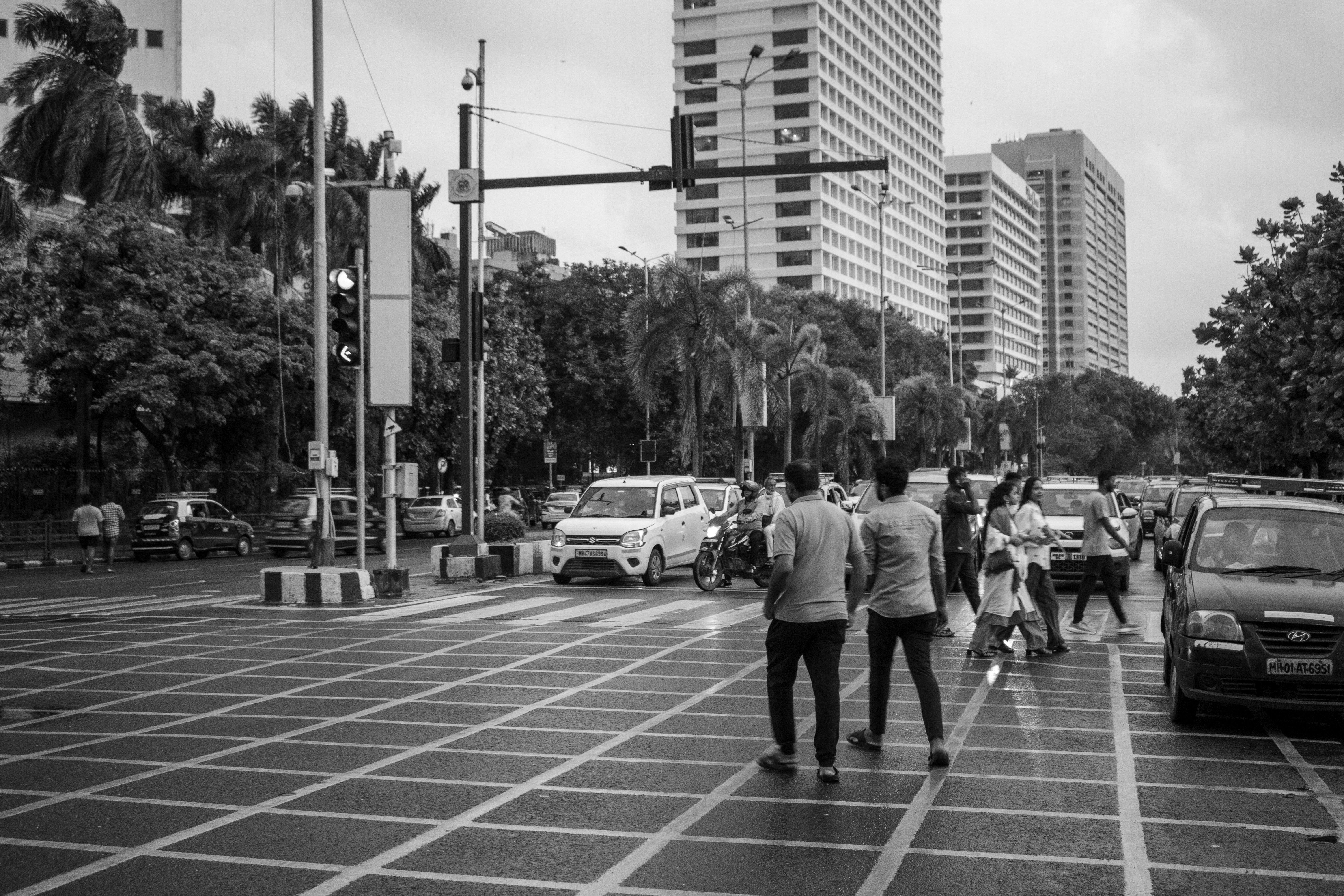 Pedestrians casually cross the road at Nariman Point, Mumbai, as cars wait at a red traffic light.