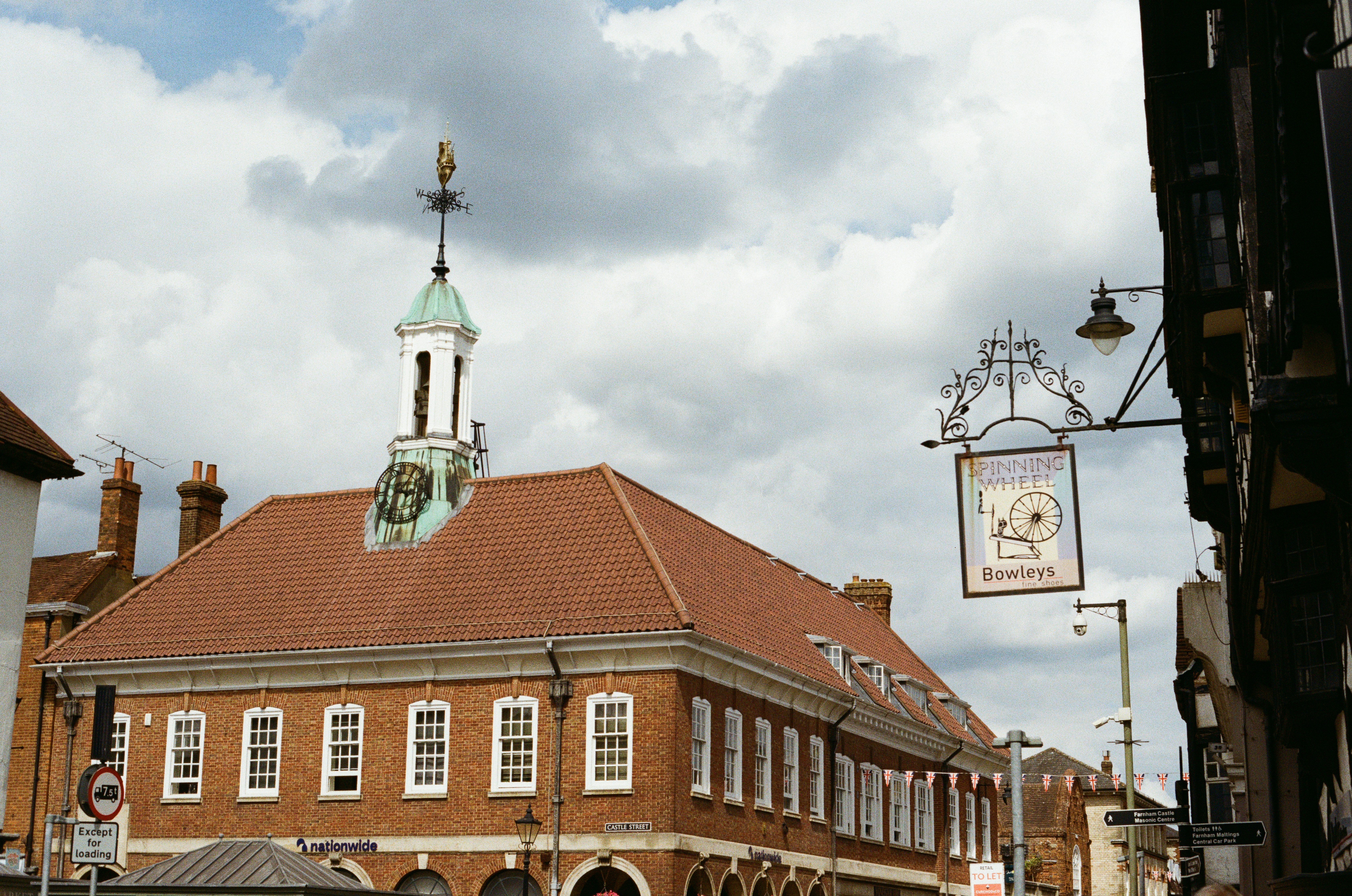 A brick building and sign stand under cloudy skies.
