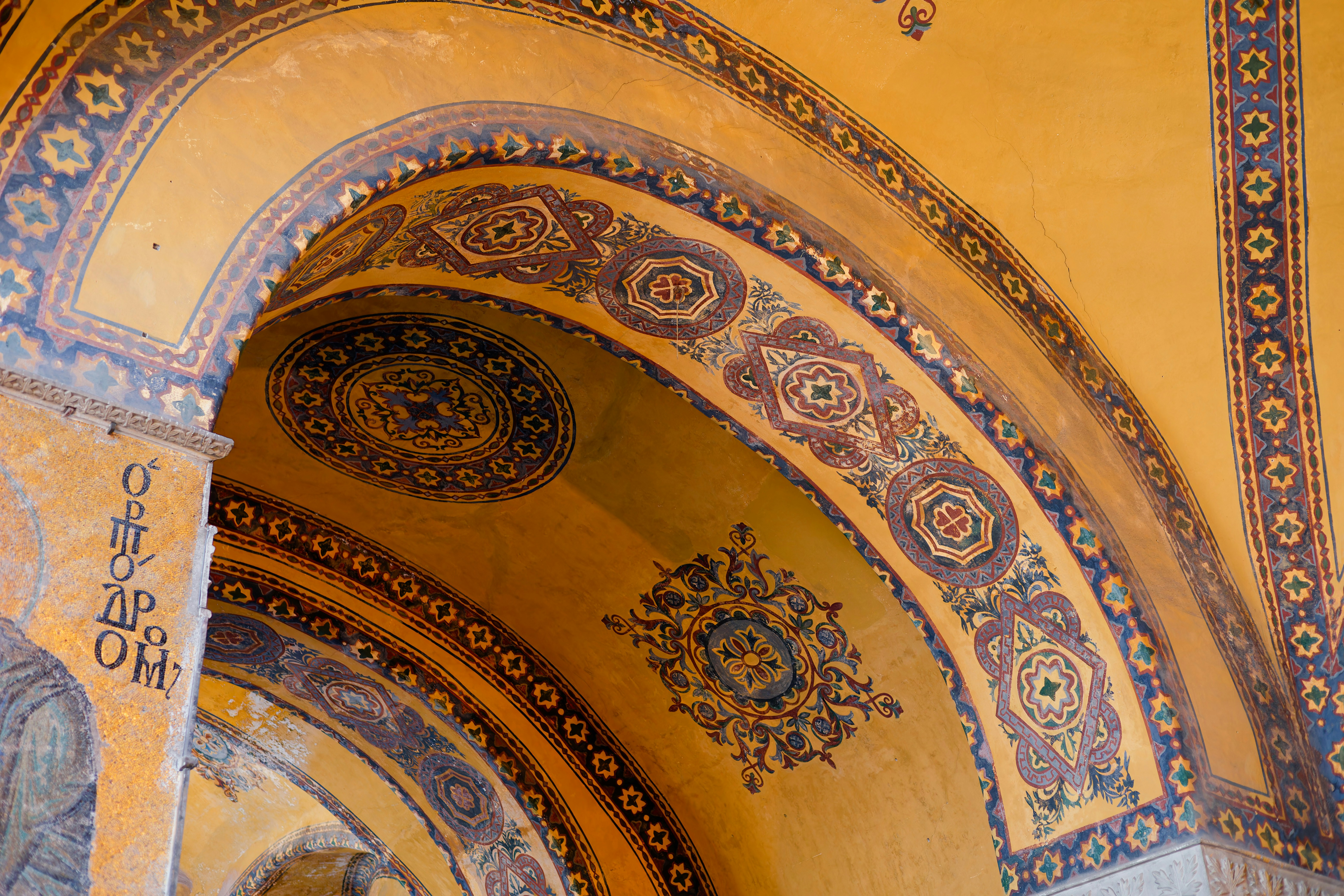 Interior of Hagia Sophia. | Ornate ceiling decorations adorn a golden arch.