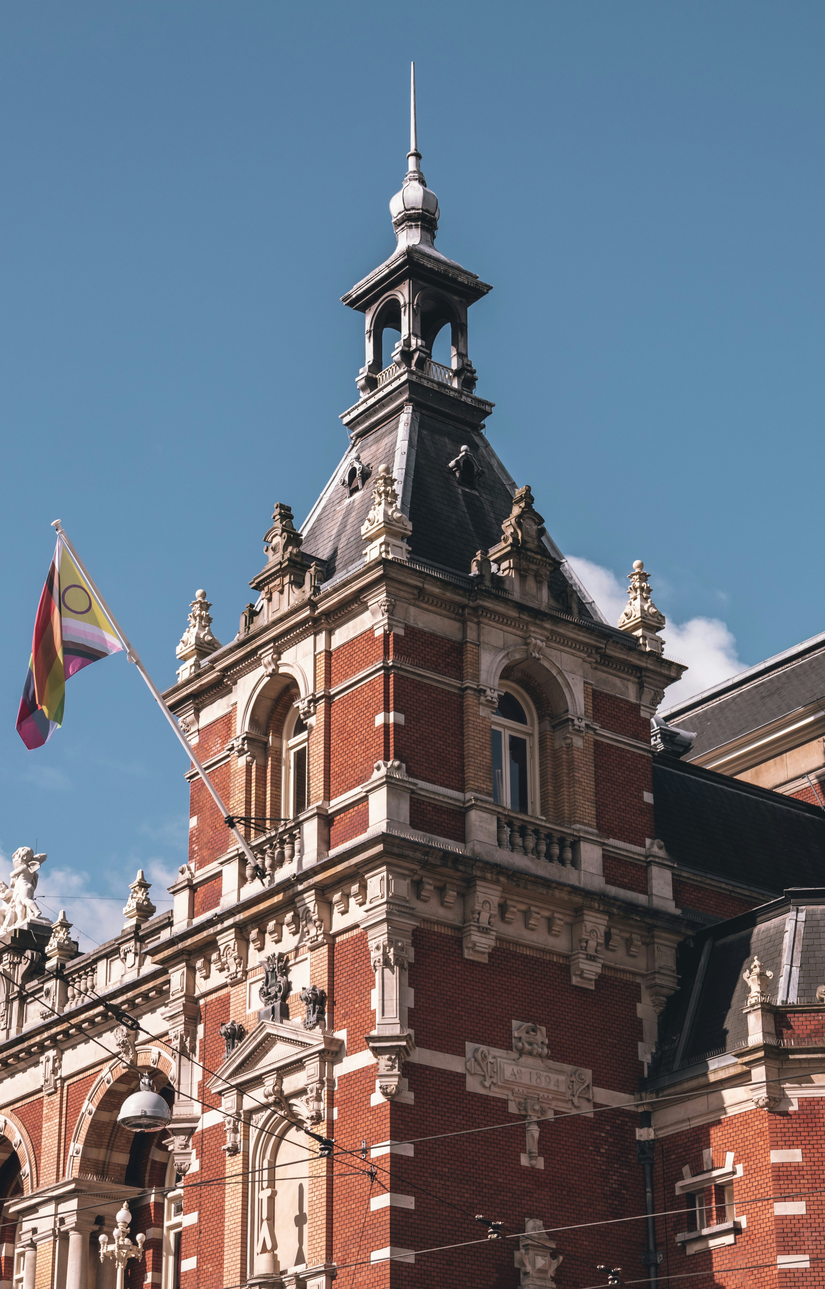 Historic city hall featuring intricate brickwork and a prominent flag fluttering in the breeze.