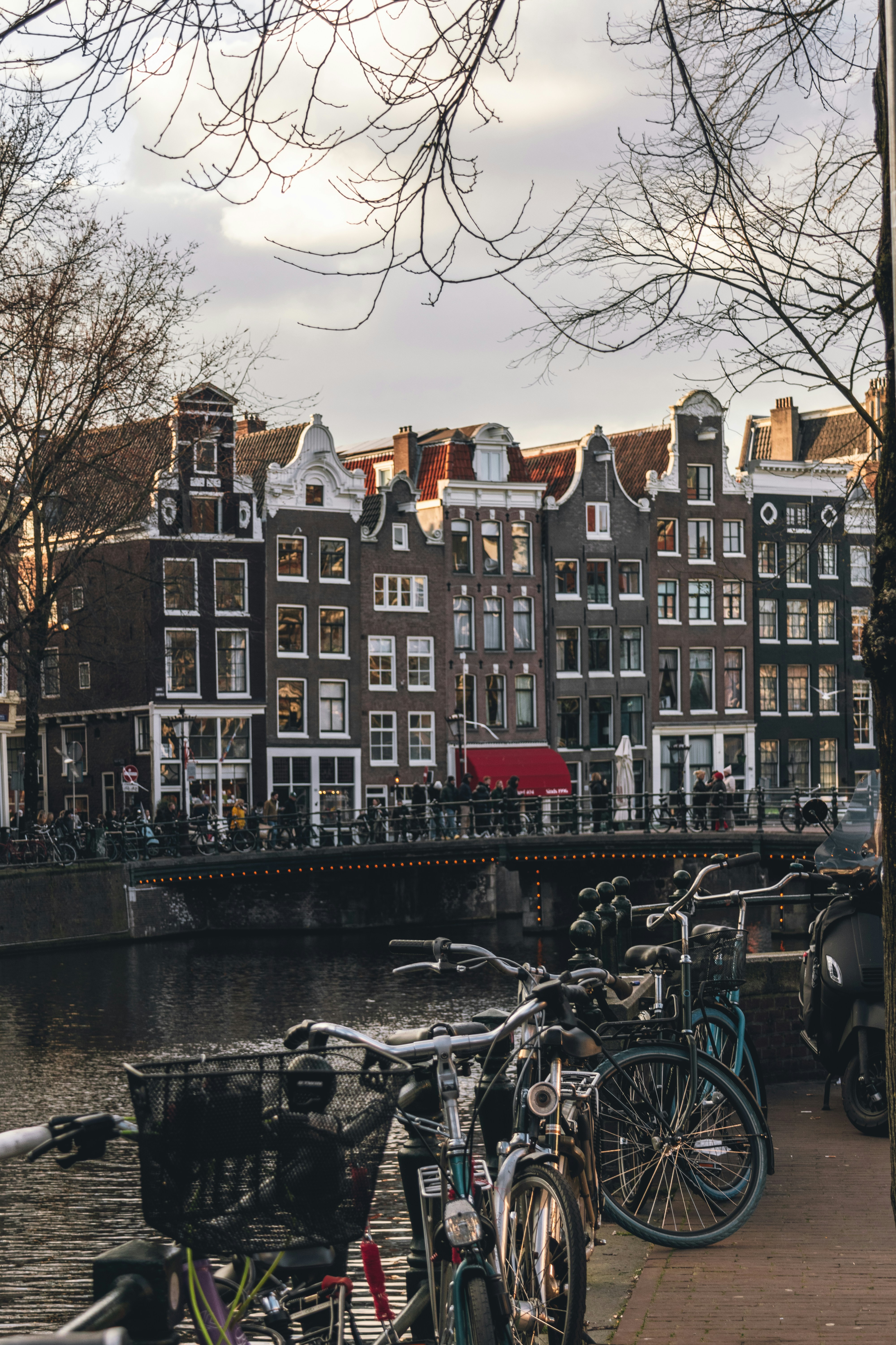 A bunch of bikes chained up by the canals in Amsterdam | Amsterdam canal with historic buildings and bikes.