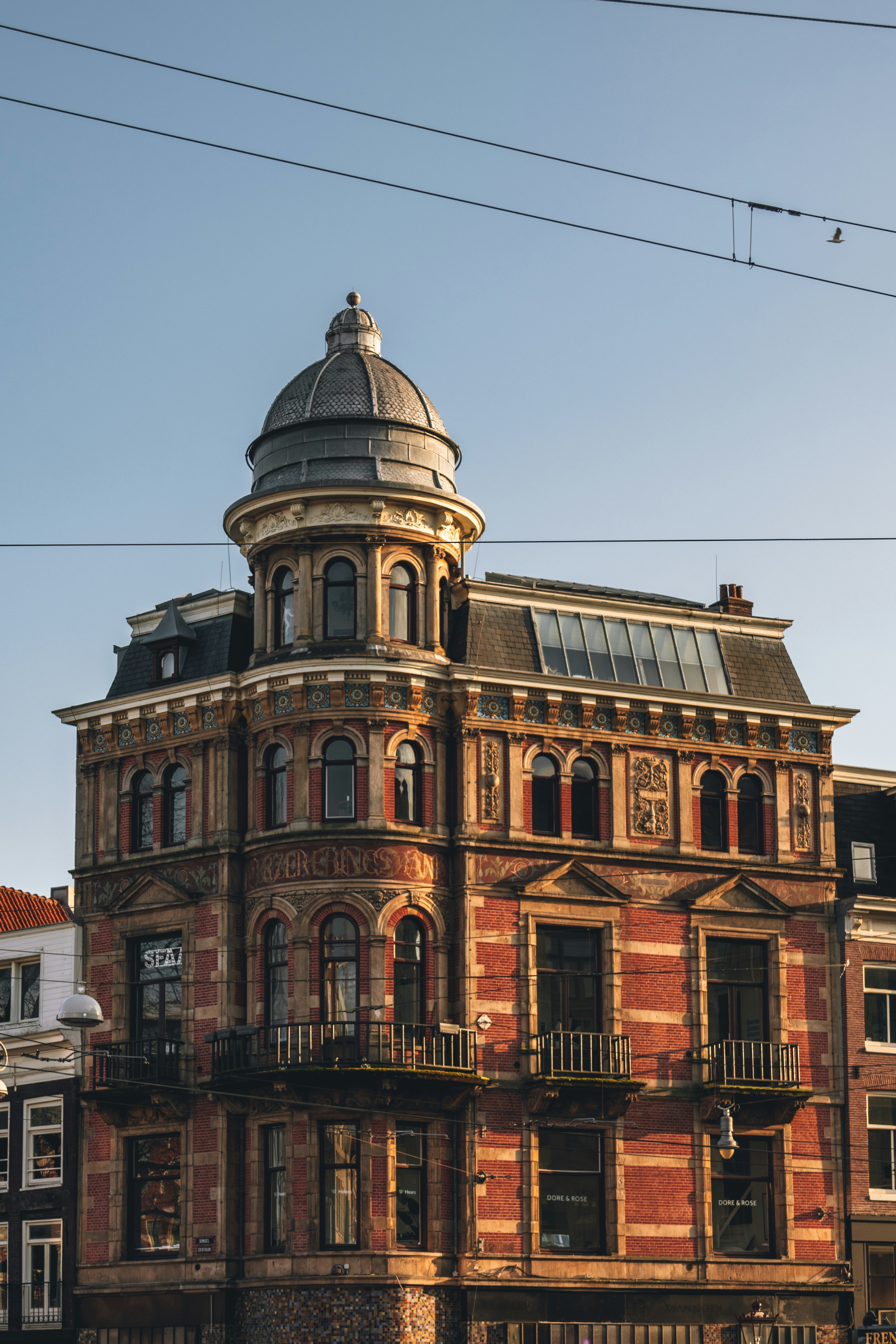 A beautiful building in the heart of Amsterdam during sunset | Ornate building with a domed turret is lit by sun.