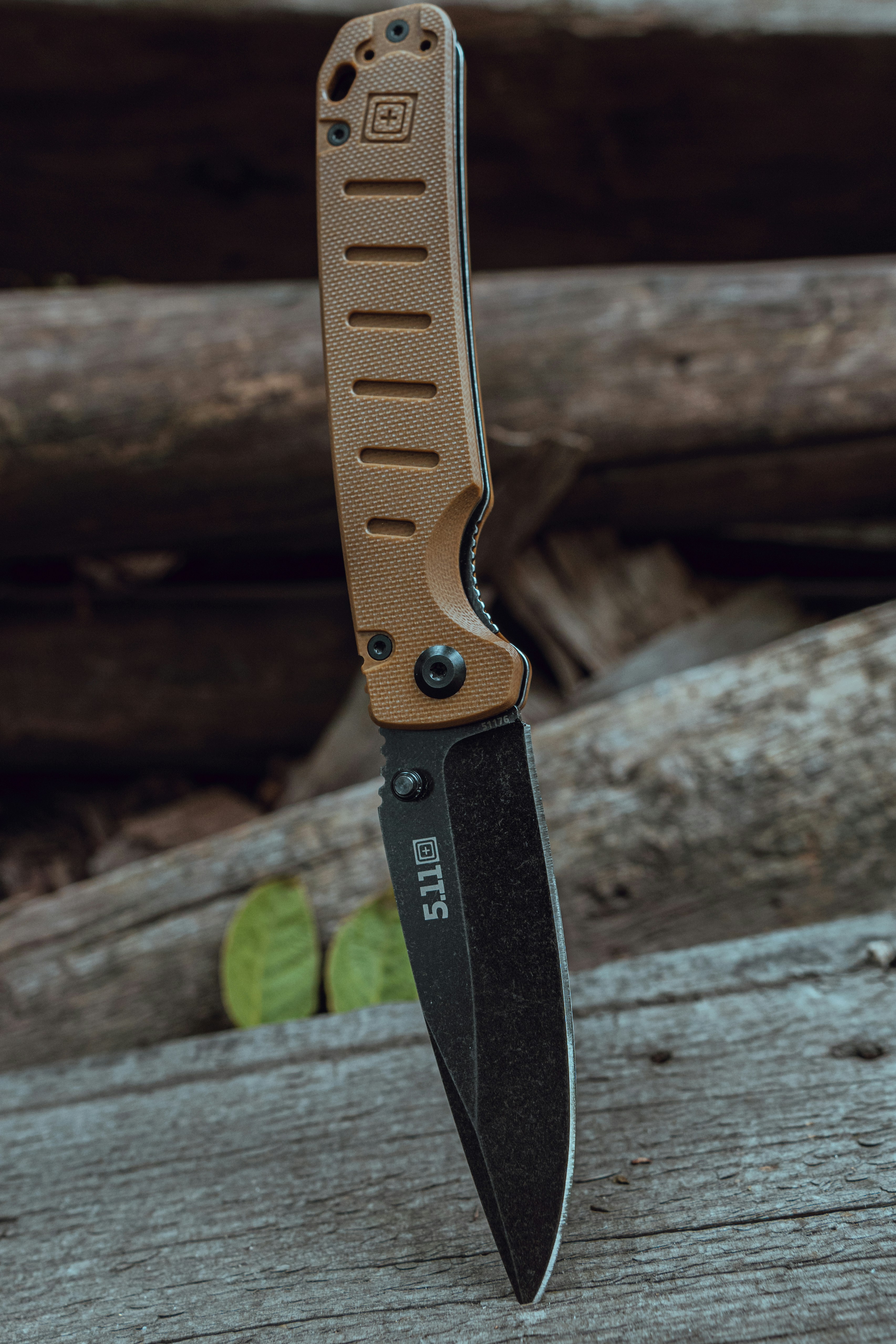 A brown folding knife rests on wood.