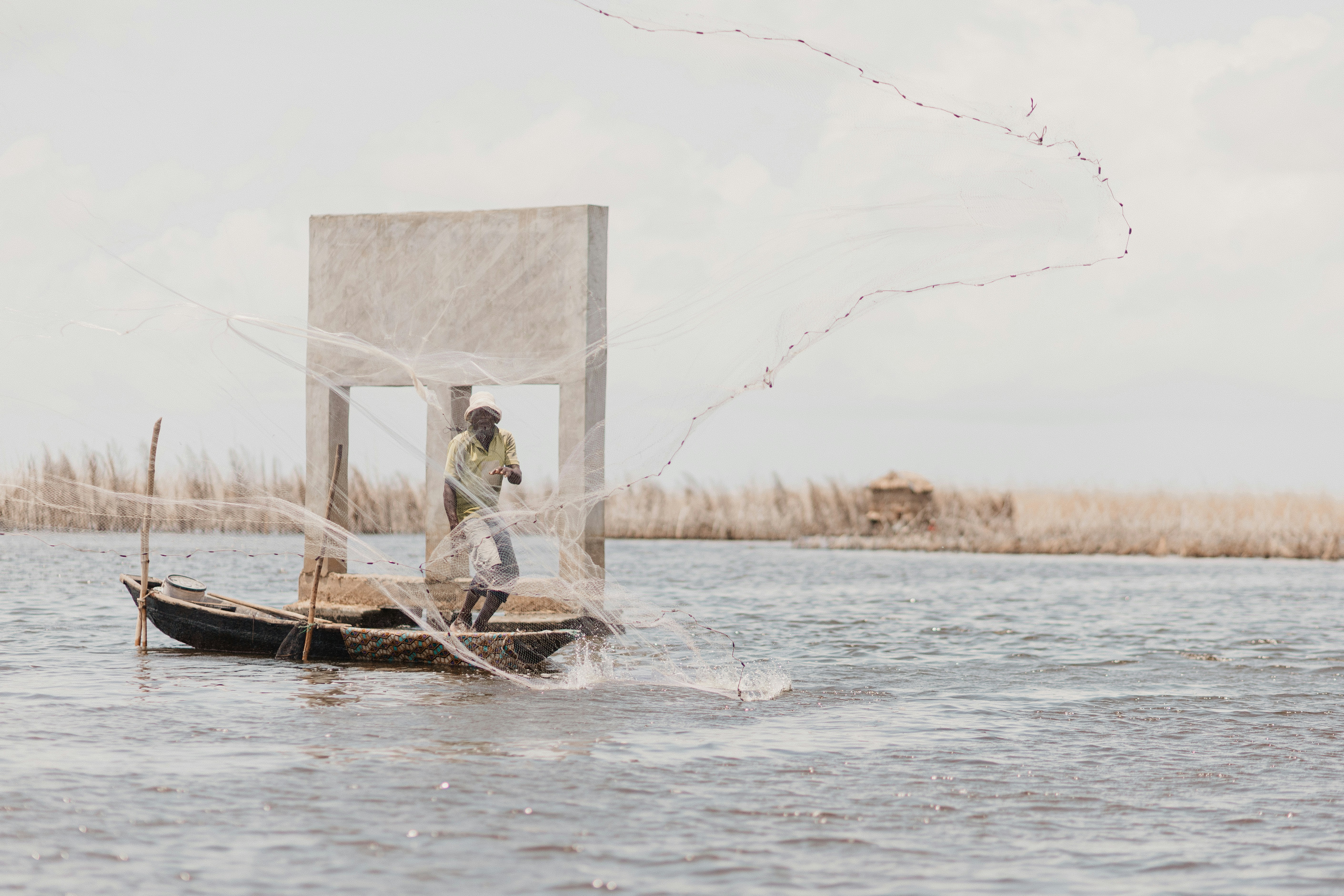 A fisherman casts his net on the water.