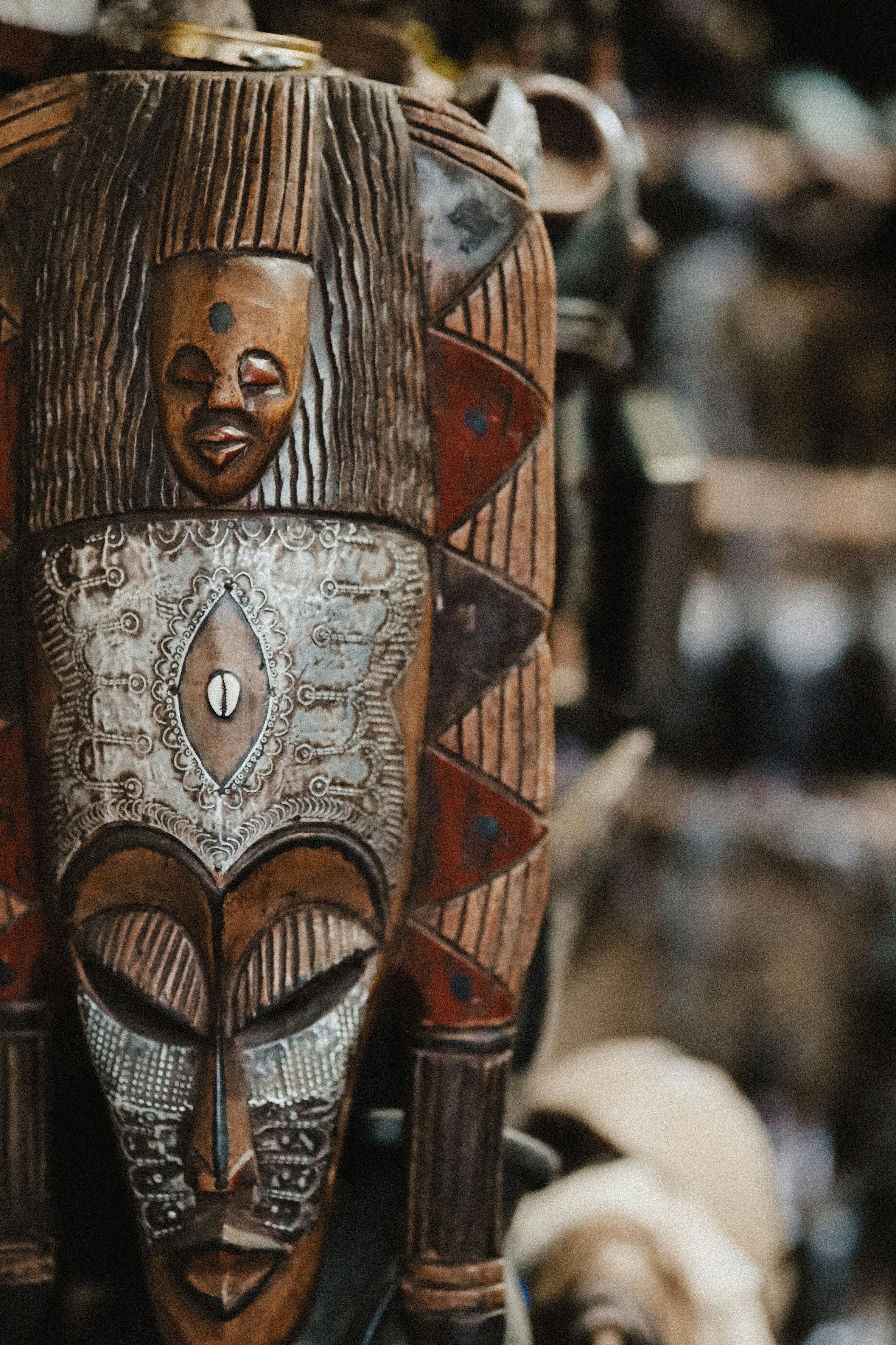 Intricately carved wooden mask featuring a prominent face and decorative elements, showcasing traditional artistry and cultural significance.