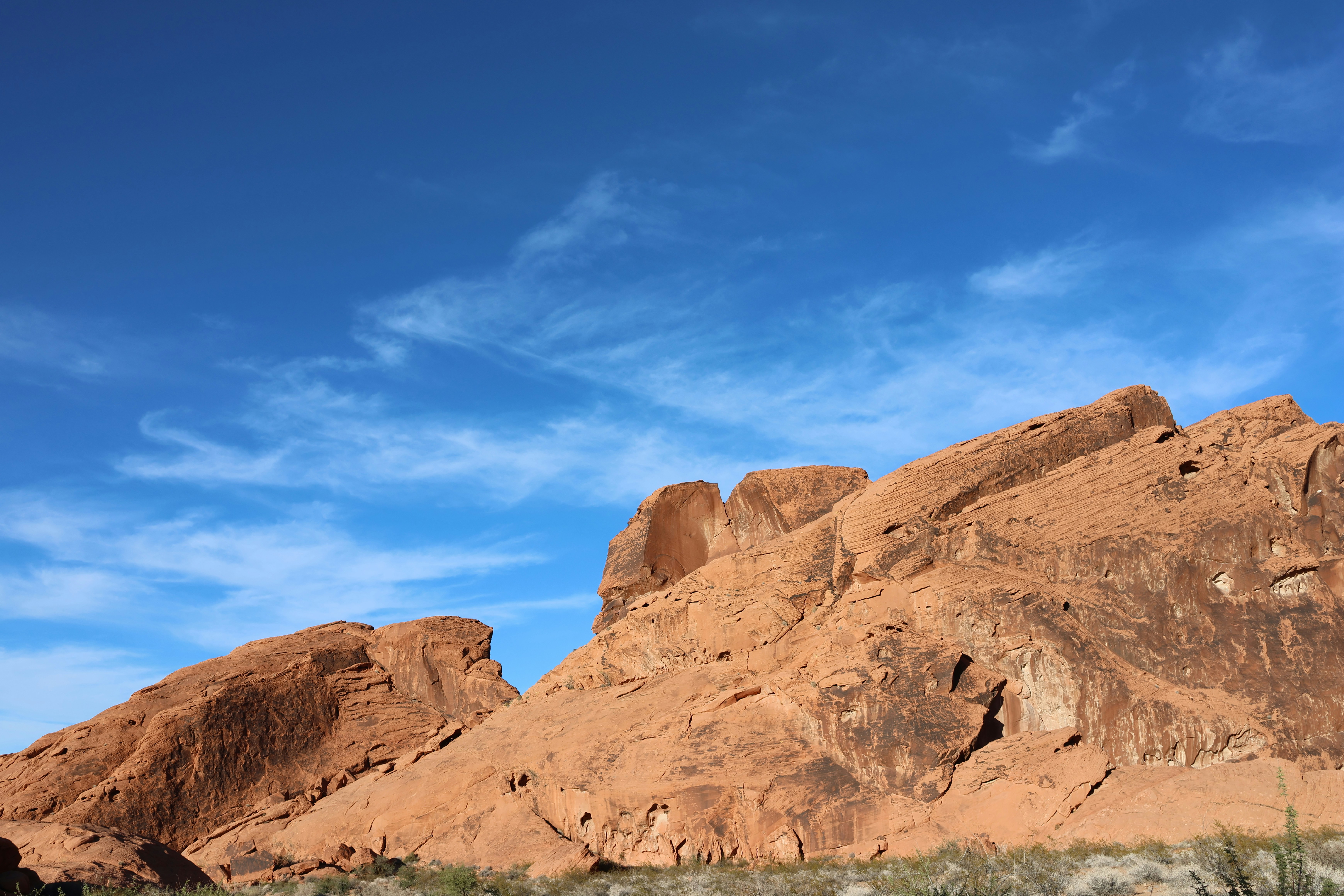 Red rocks stand against a bright blue sky.