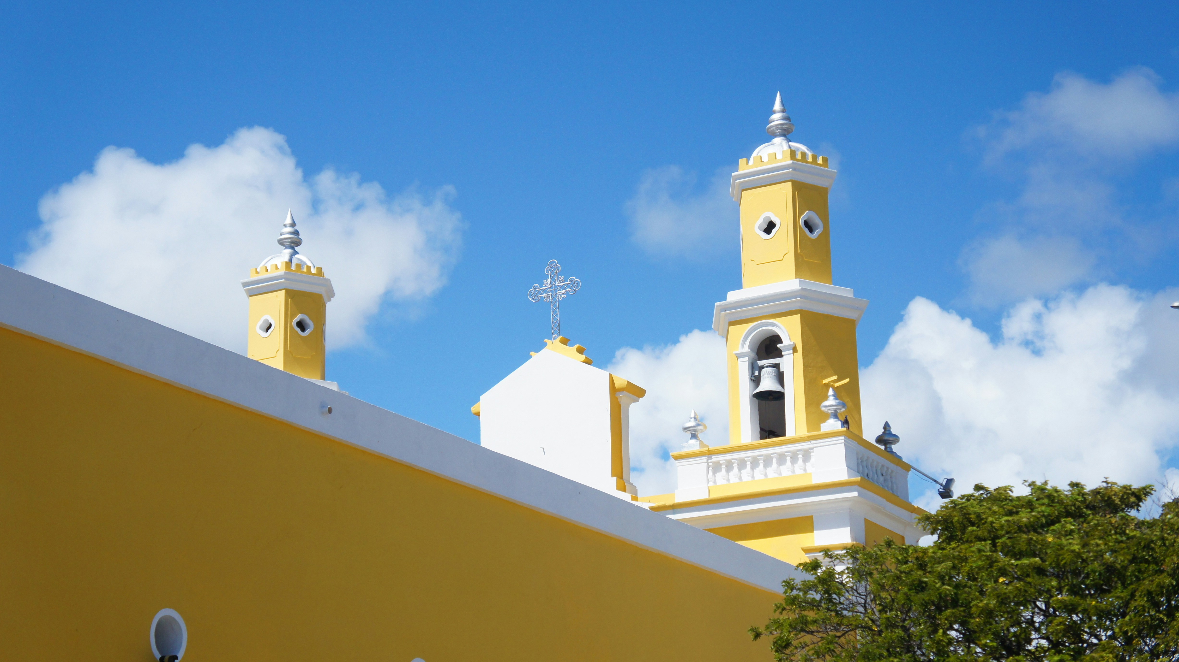 Yellow church towers under a blue sky.