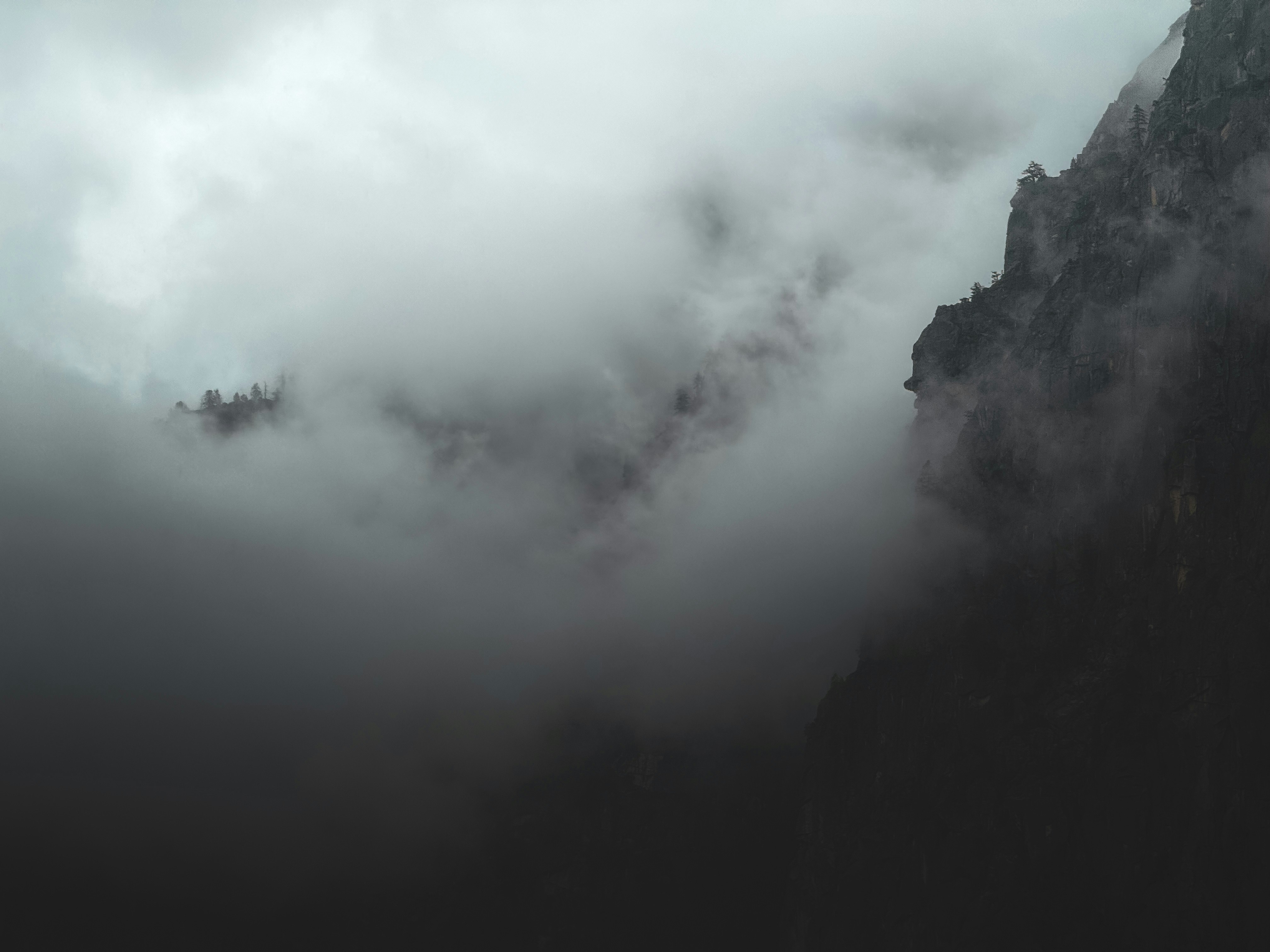 Clouds obscure a mountainous landscape's rugged edge.