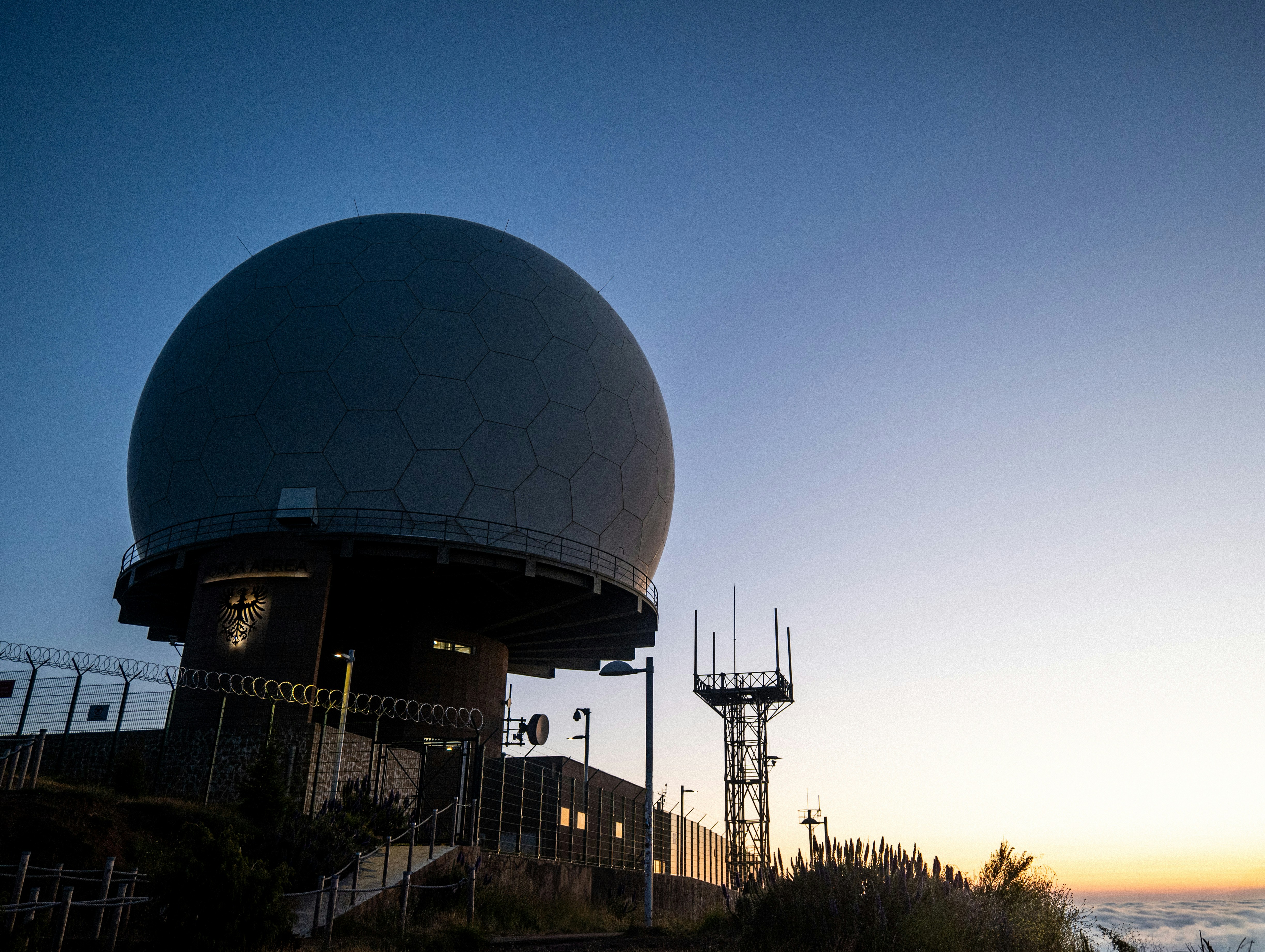 A radar dome silhouetted against a blue sky.