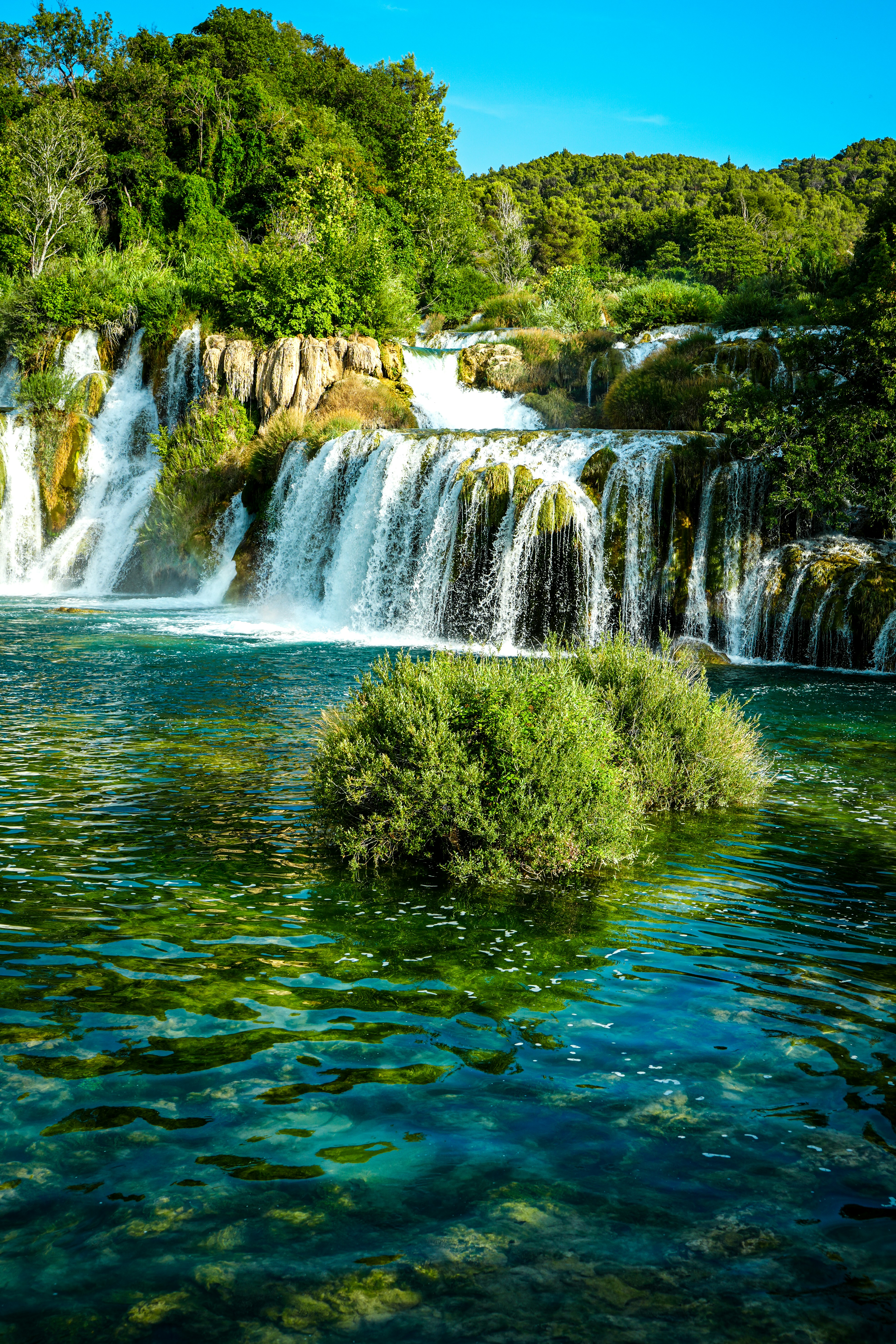 Waterfalls cascade into a beautiful, clear blue lake. photo – Free ...