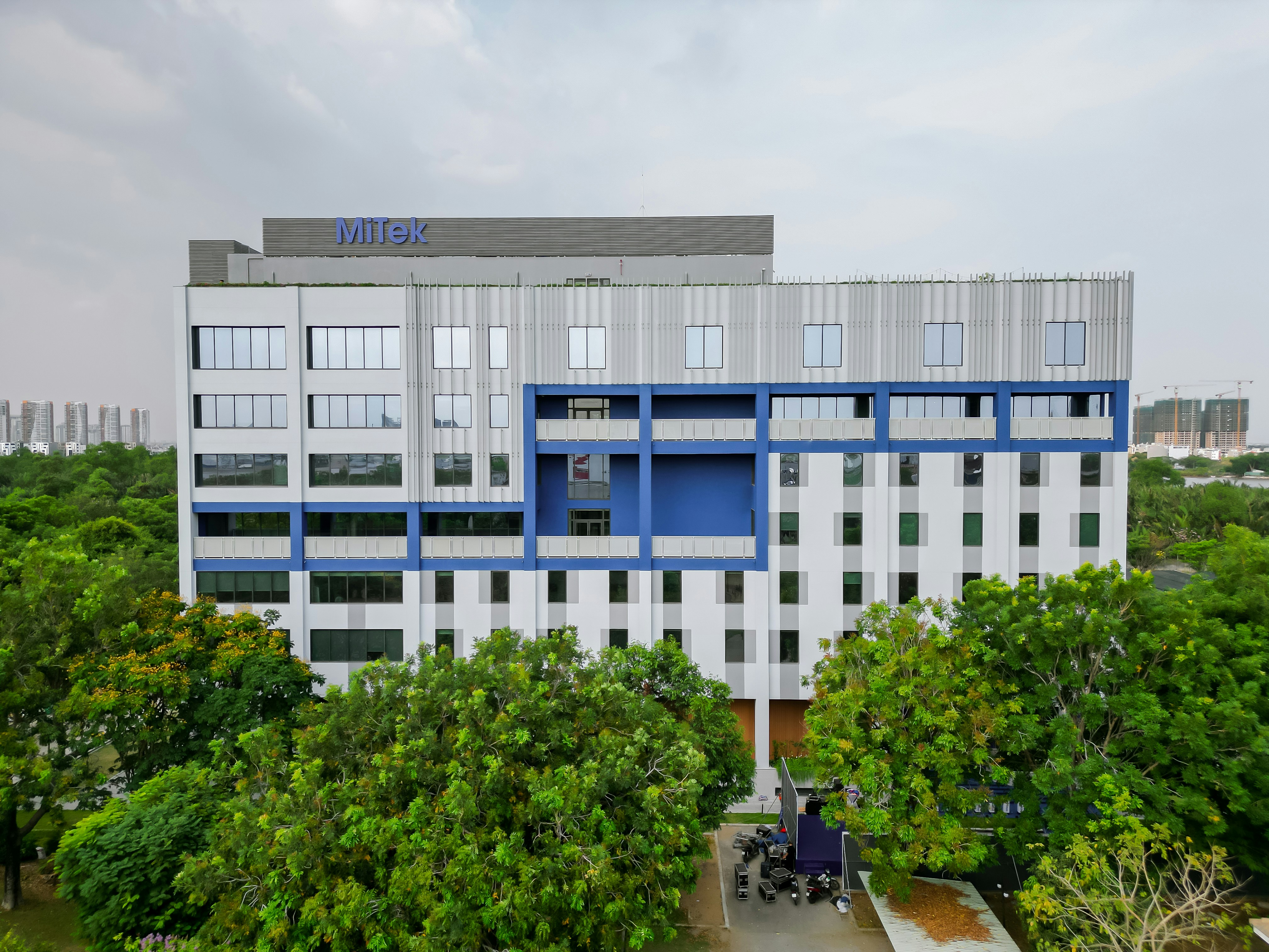 Modern building stands surrounded by green trees.