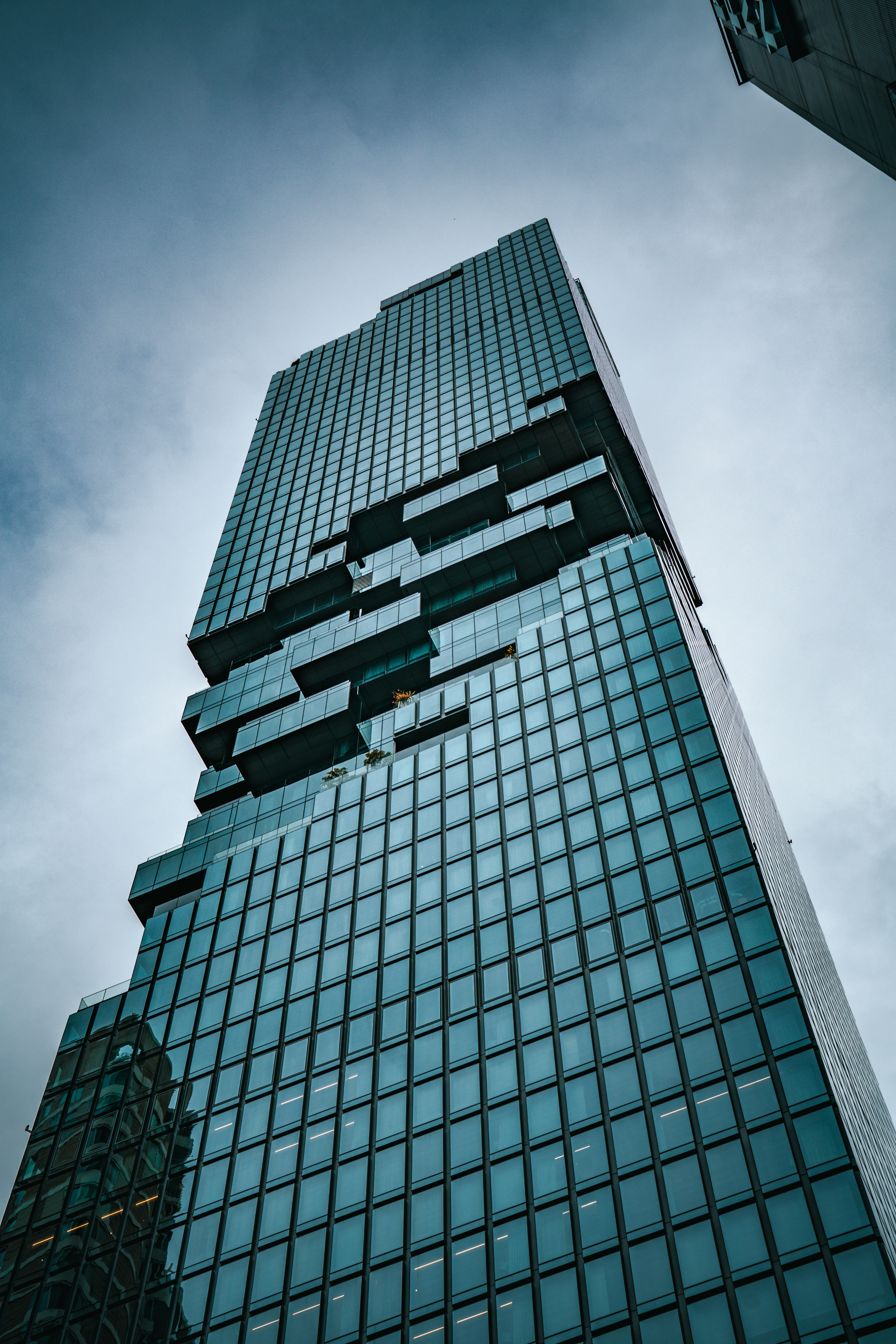 A modern skyscraper towers toward a cloudy sky.