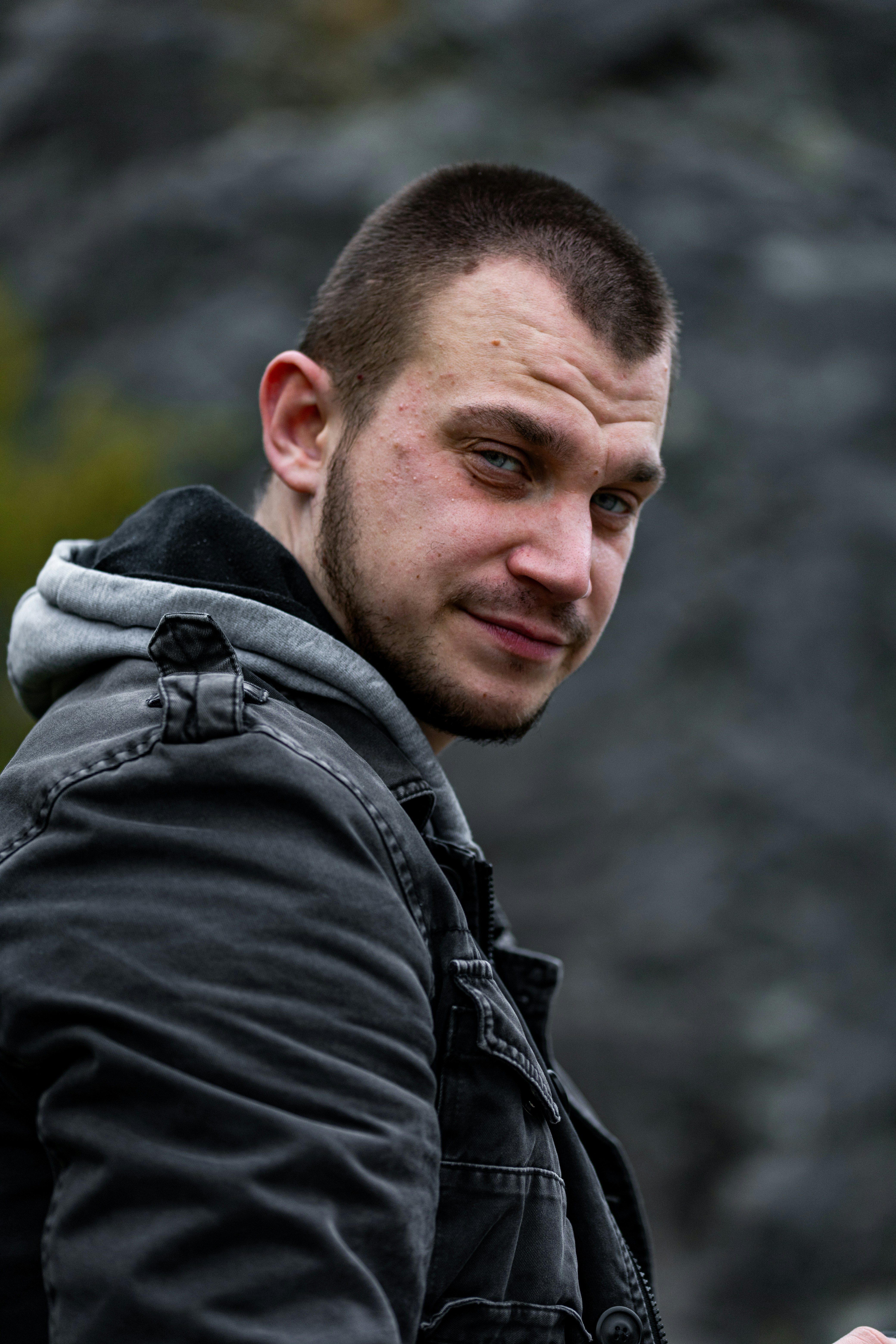Model vor Wand | A man smiles, looking over his shoulder.