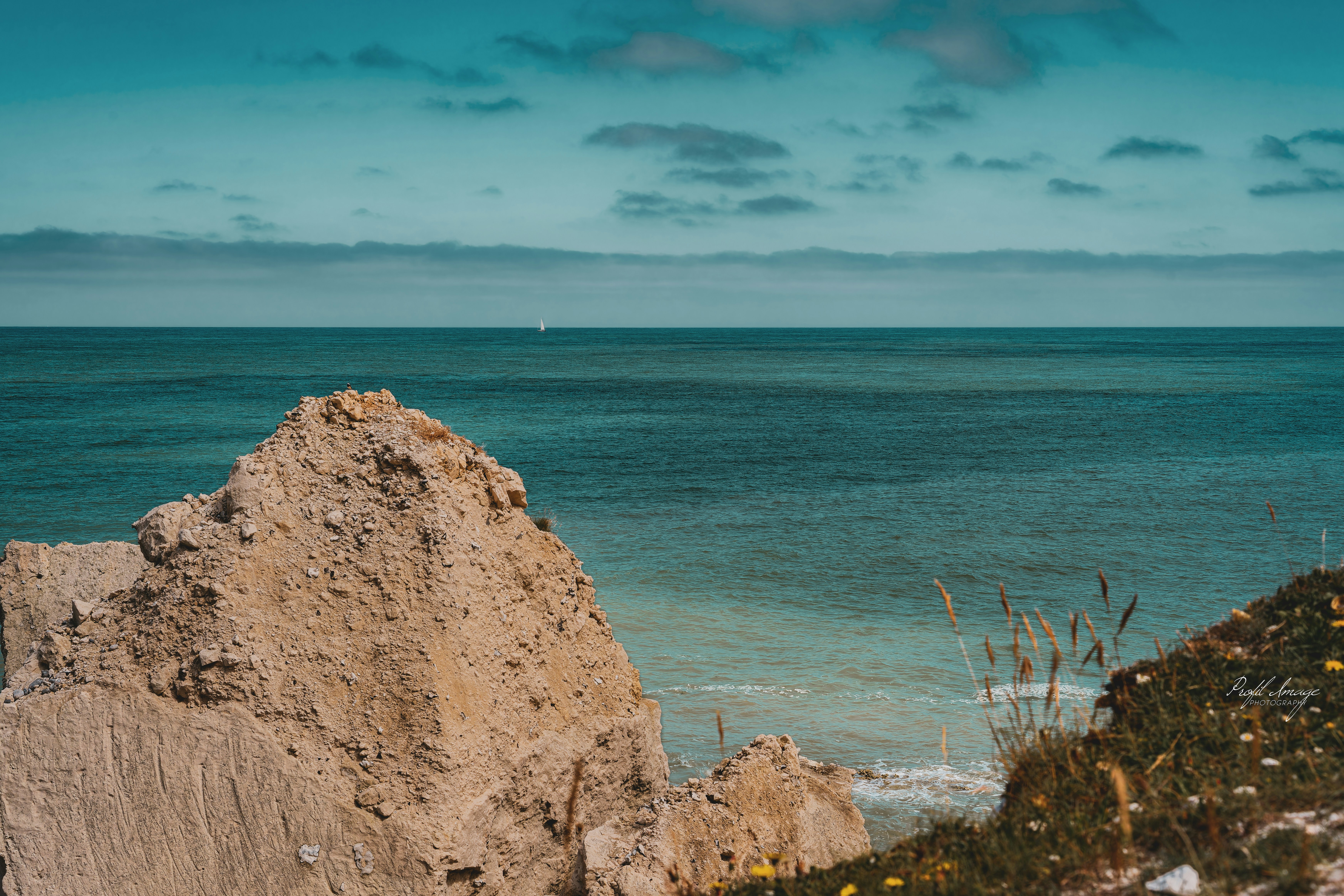 Rocky cliffs overlook a calm, blue ocean.