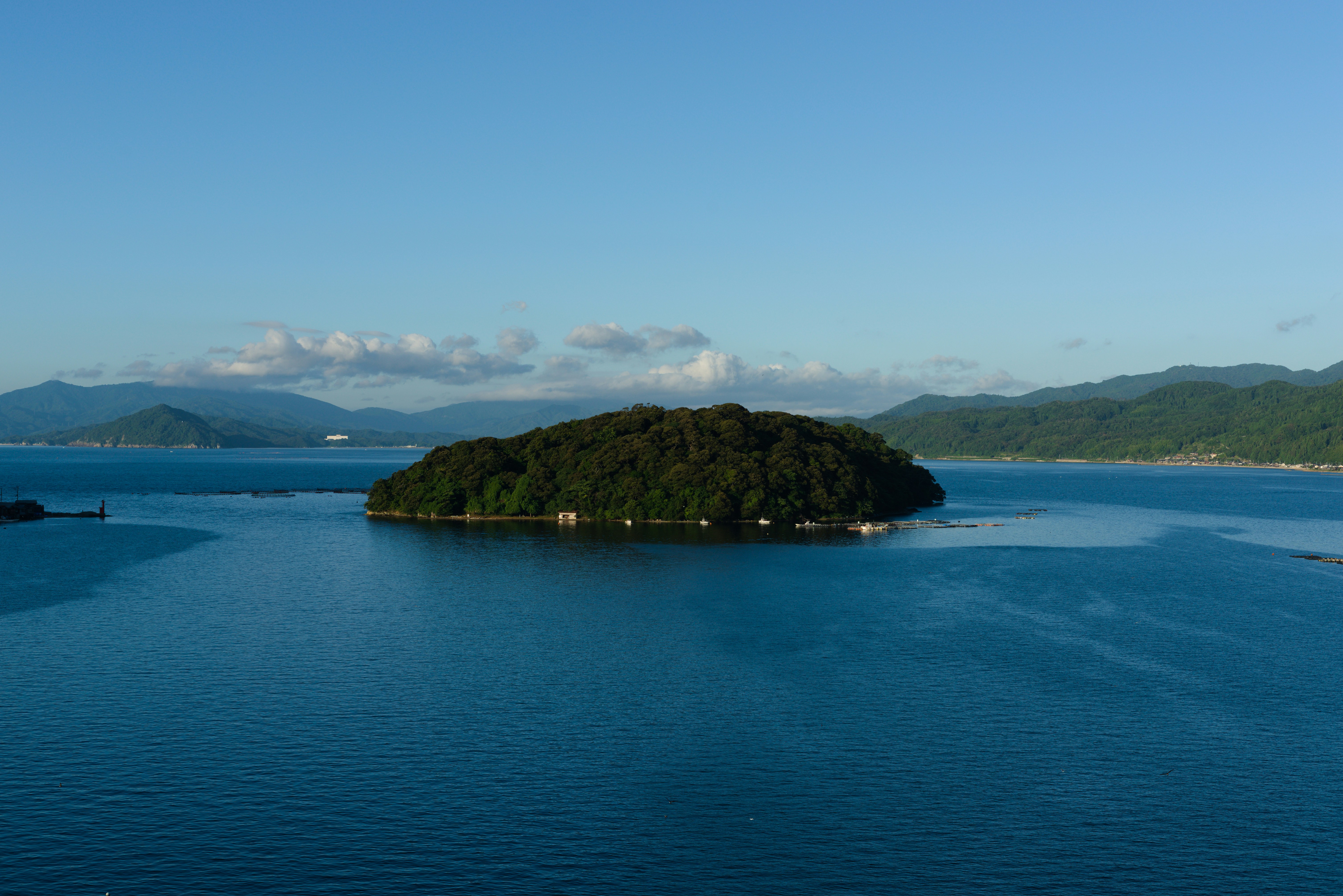 An island sits surrounded by calm, blue water.