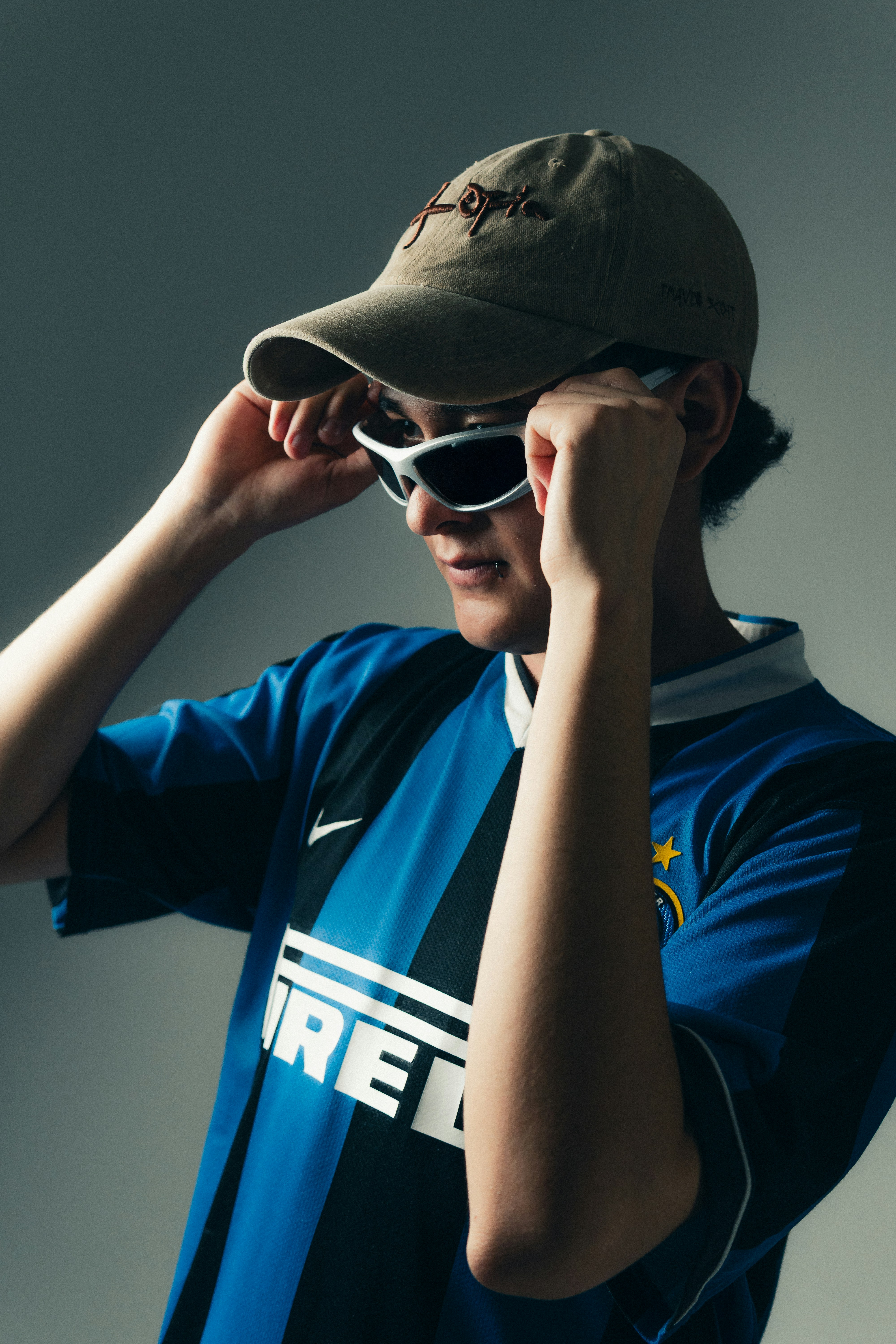 A person is adjusting their sunglasses and hat.