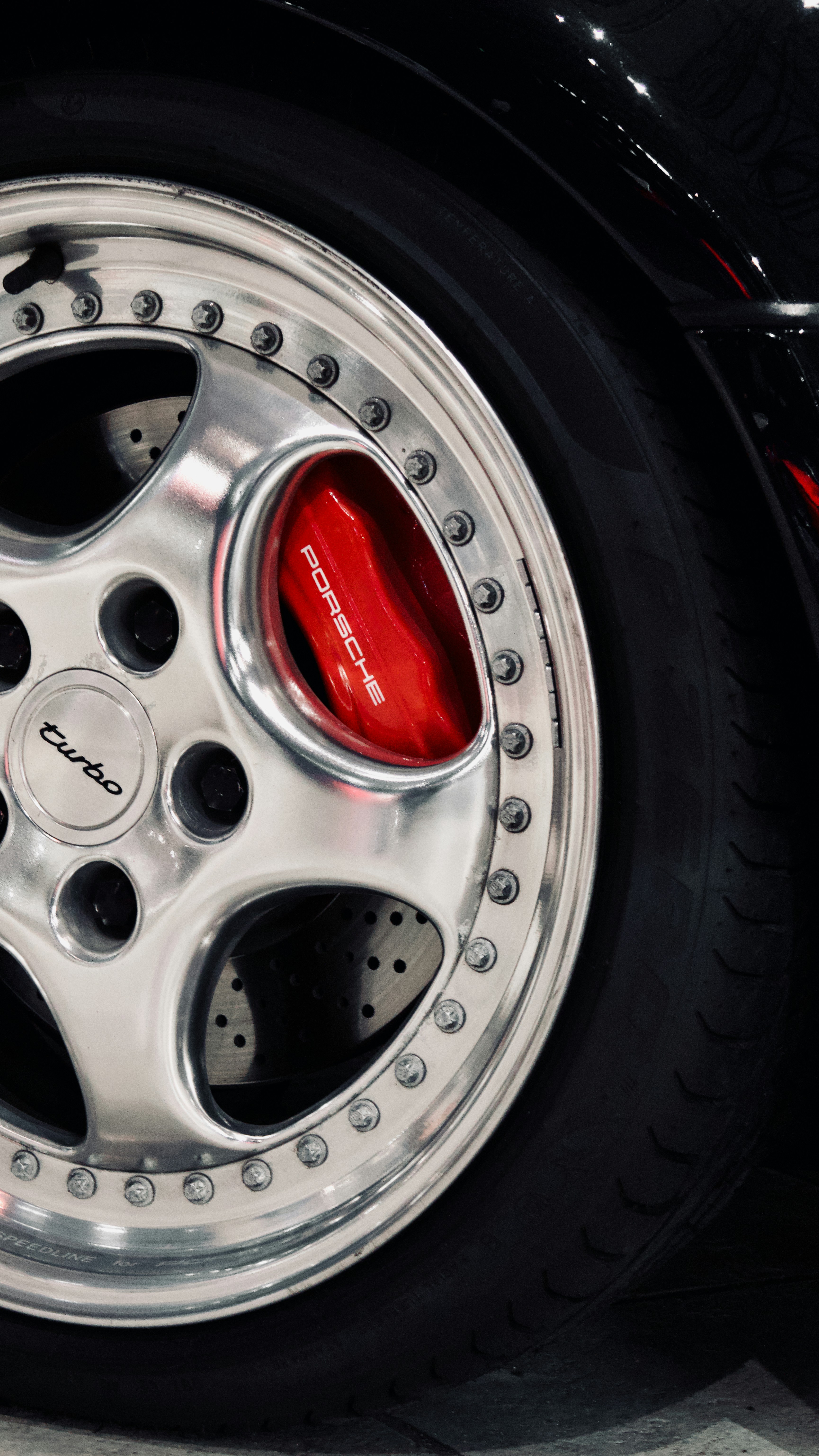 A shiny porsche wheel with red brake caliper.
