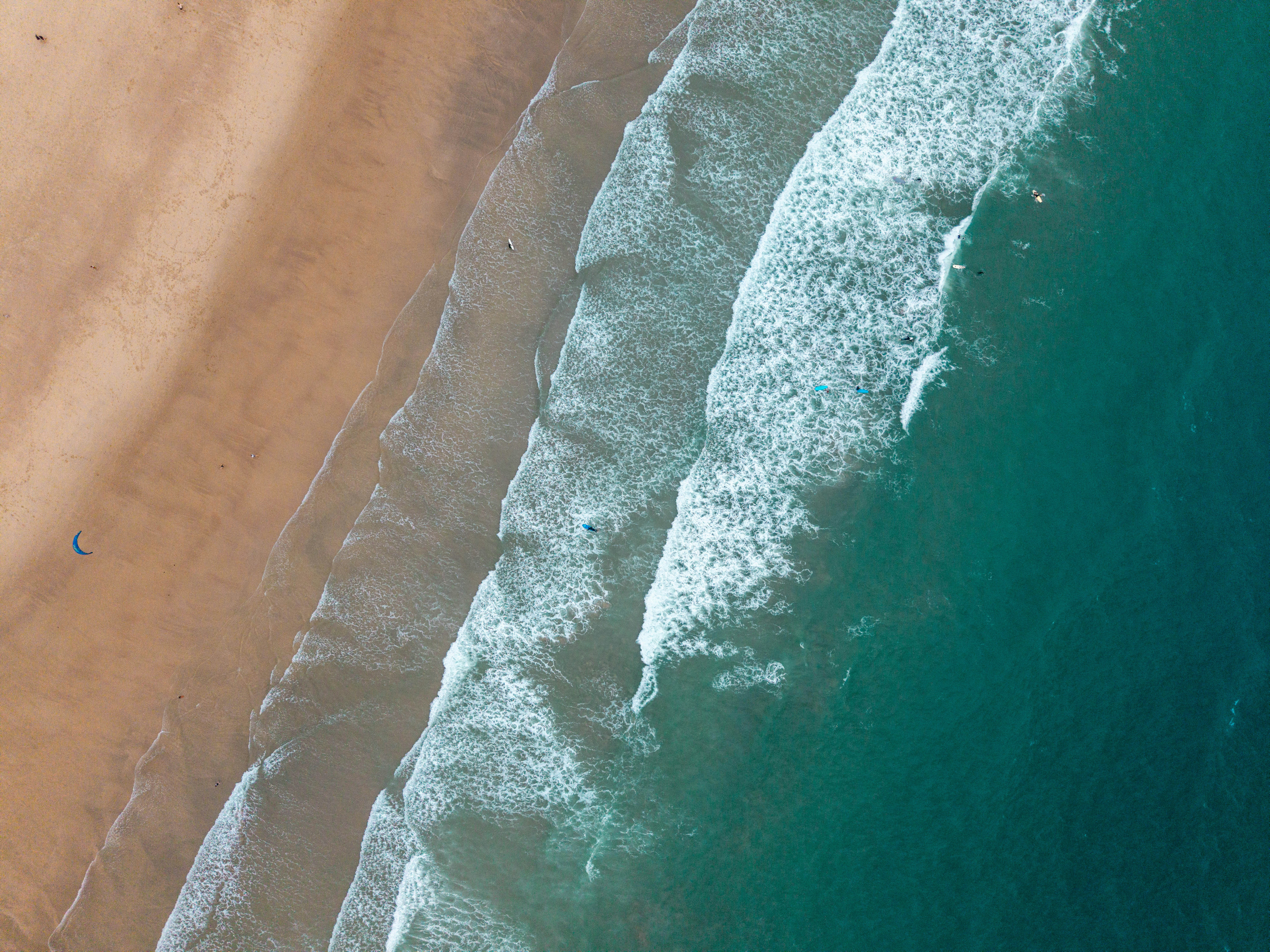 How many stories are written in the curves of each passing wave? | Waves crash onto a sandy beach.