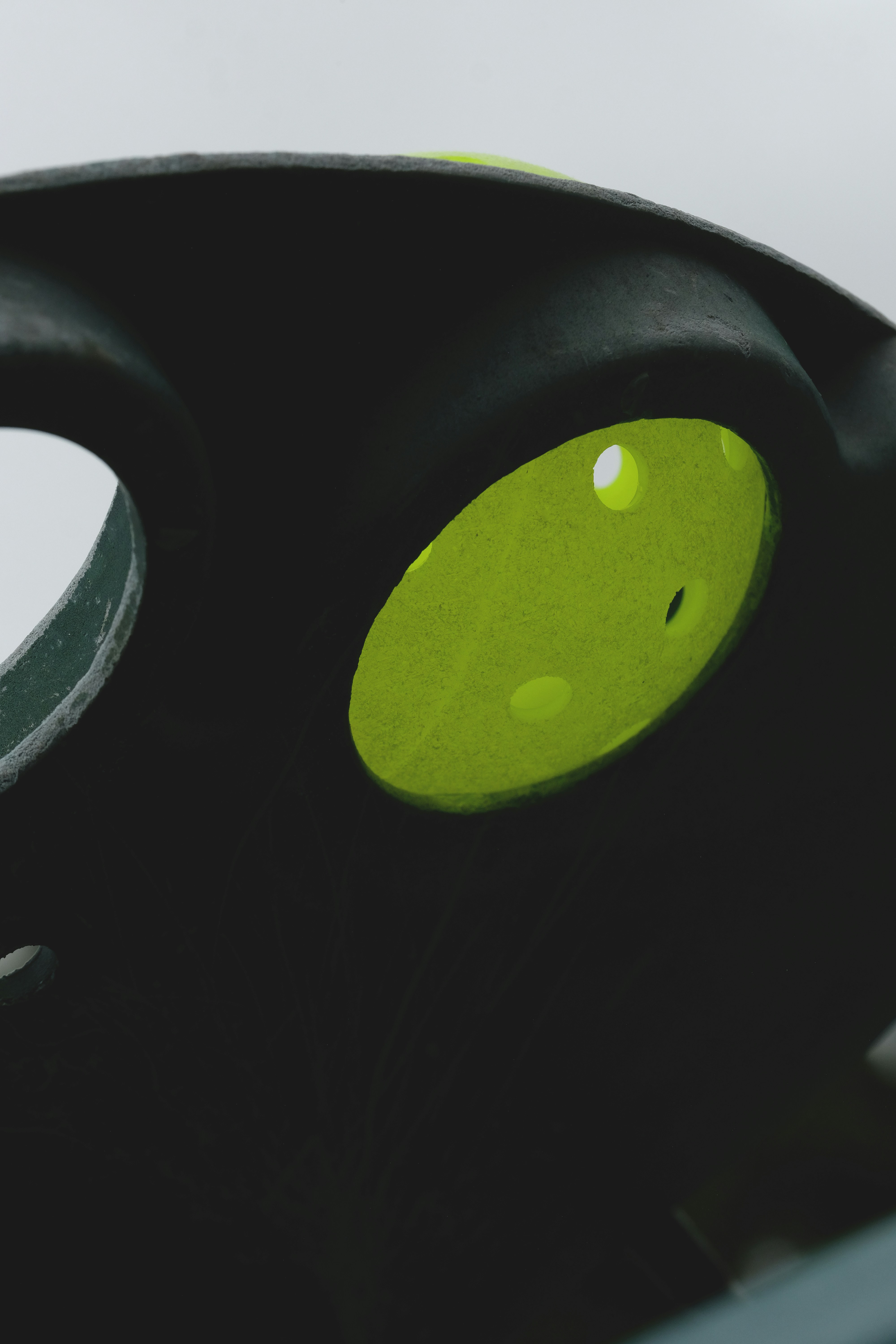 pickleball from underneath | An abstract close-up shows holes and green.