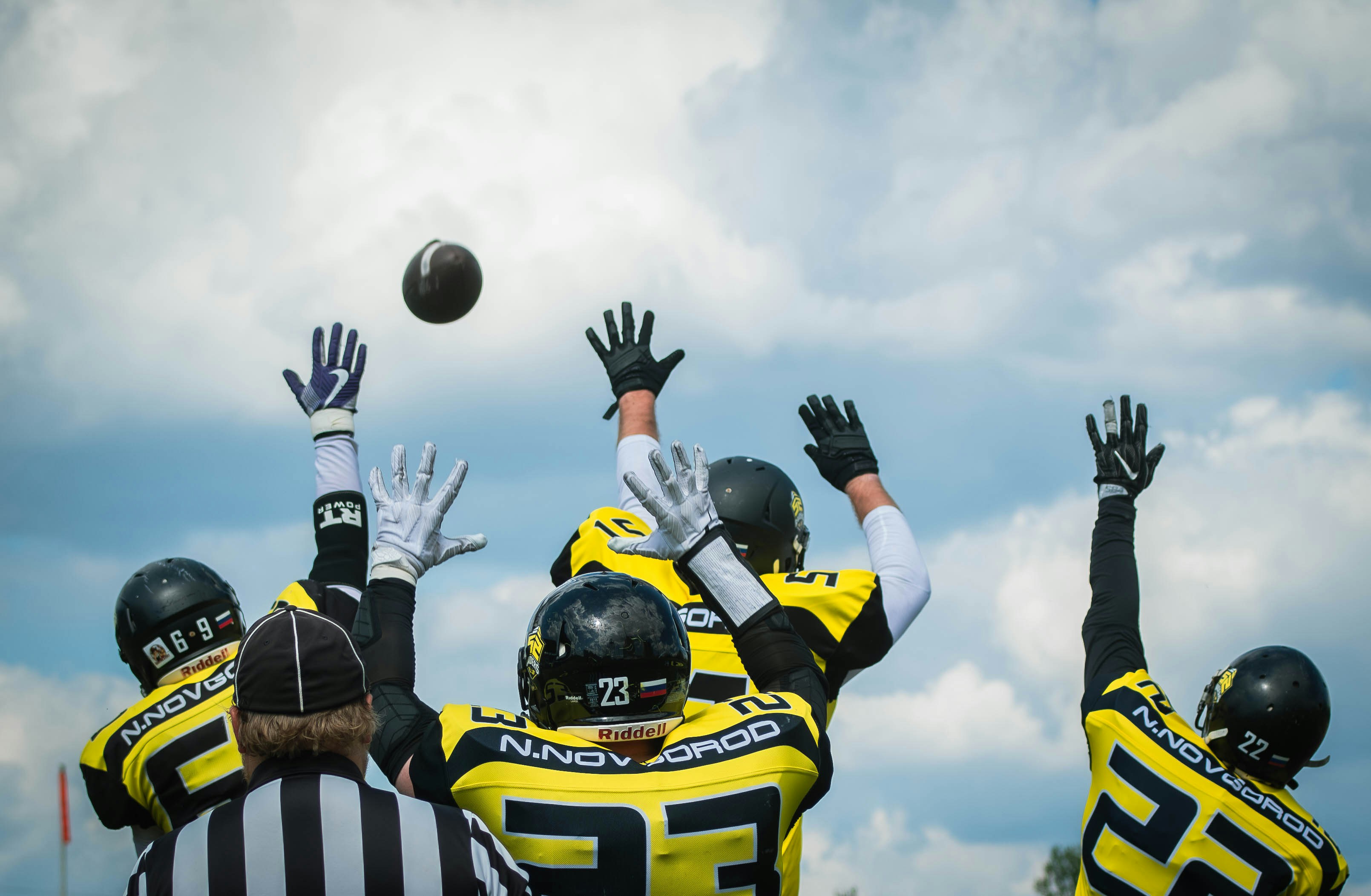 Football players jump to catch the football.