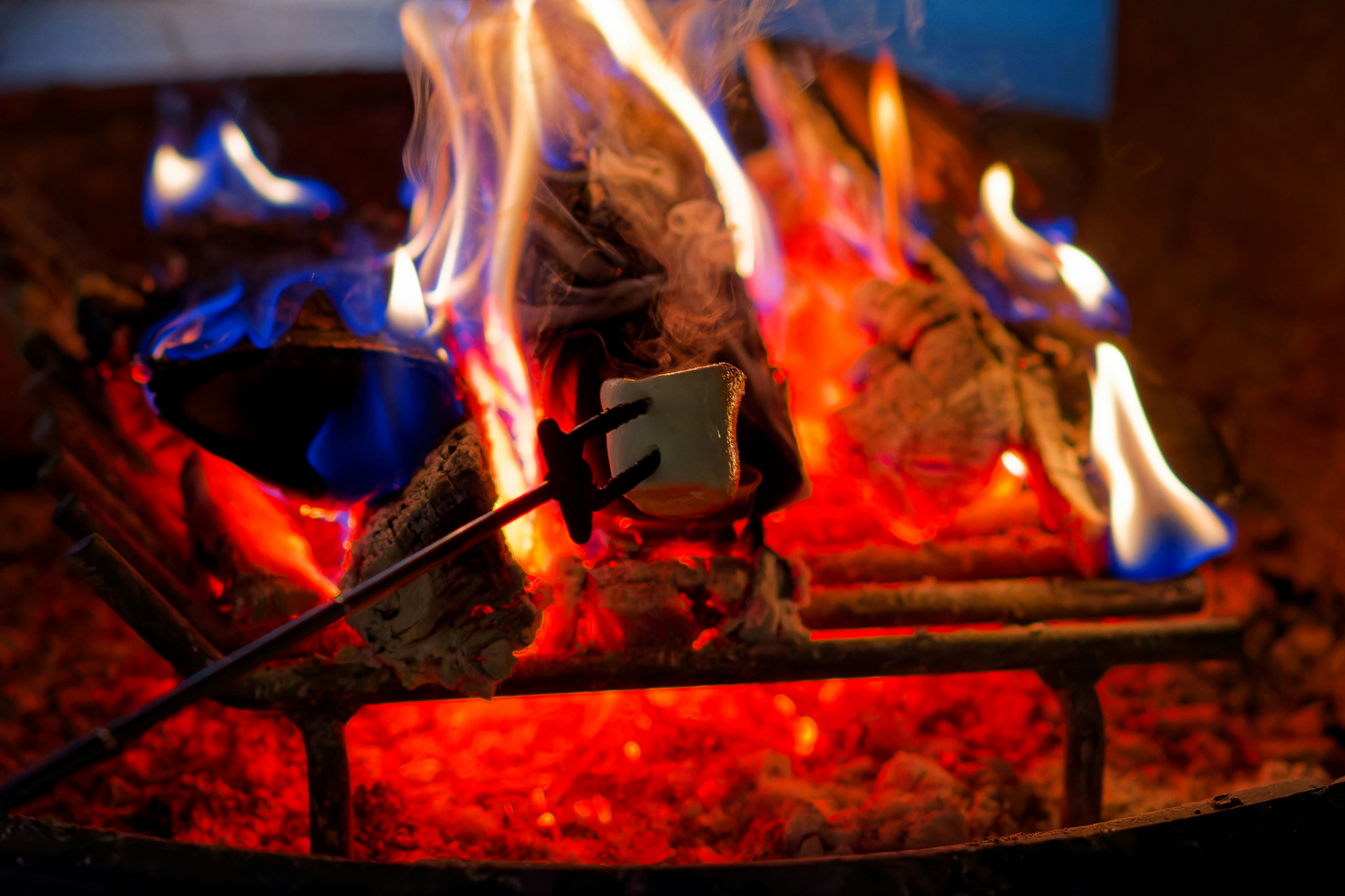 Roasting marshmallows by the fire | Marshmallow being roasted over a roaring fire.