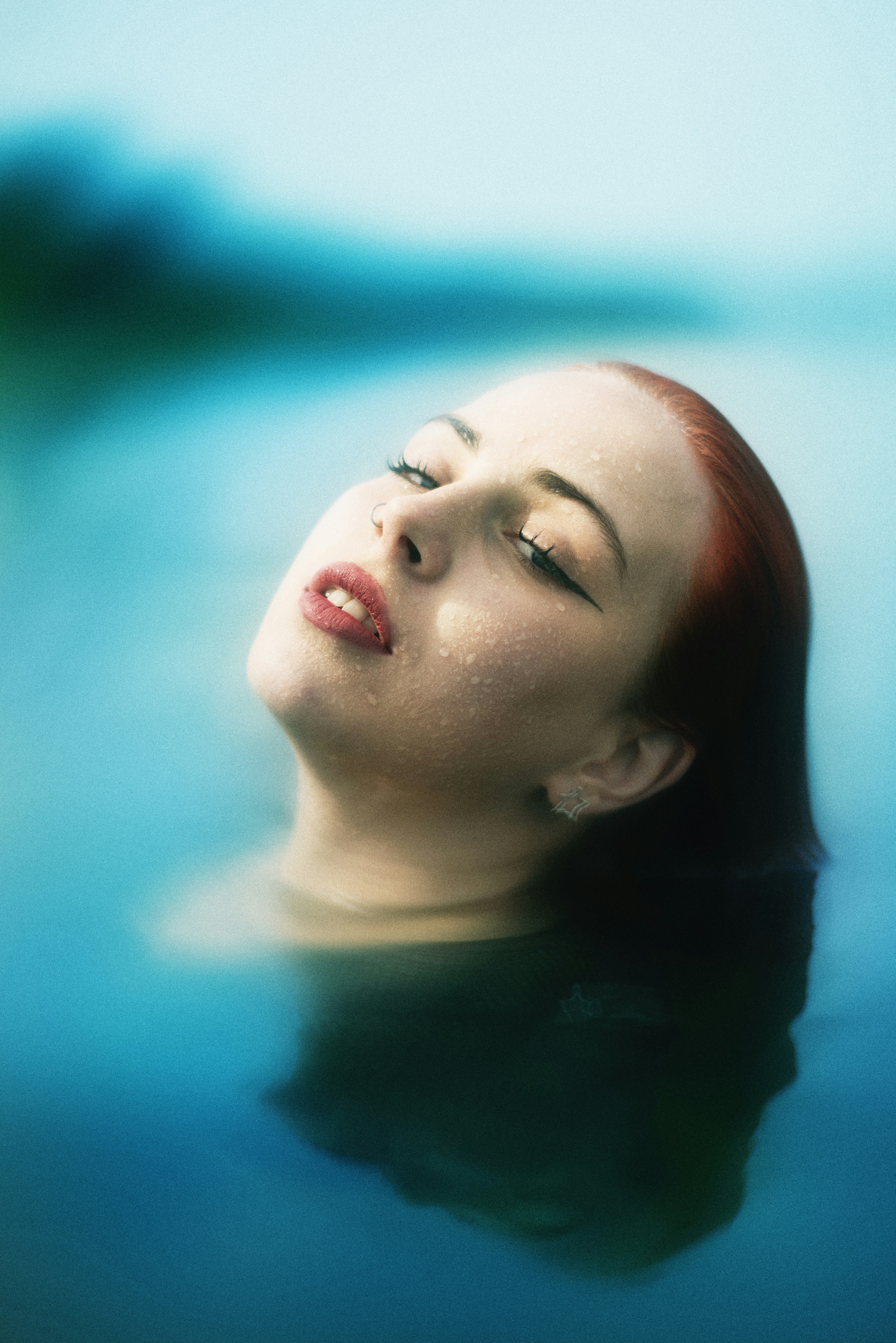 Woman emerges from water with eyes closed.