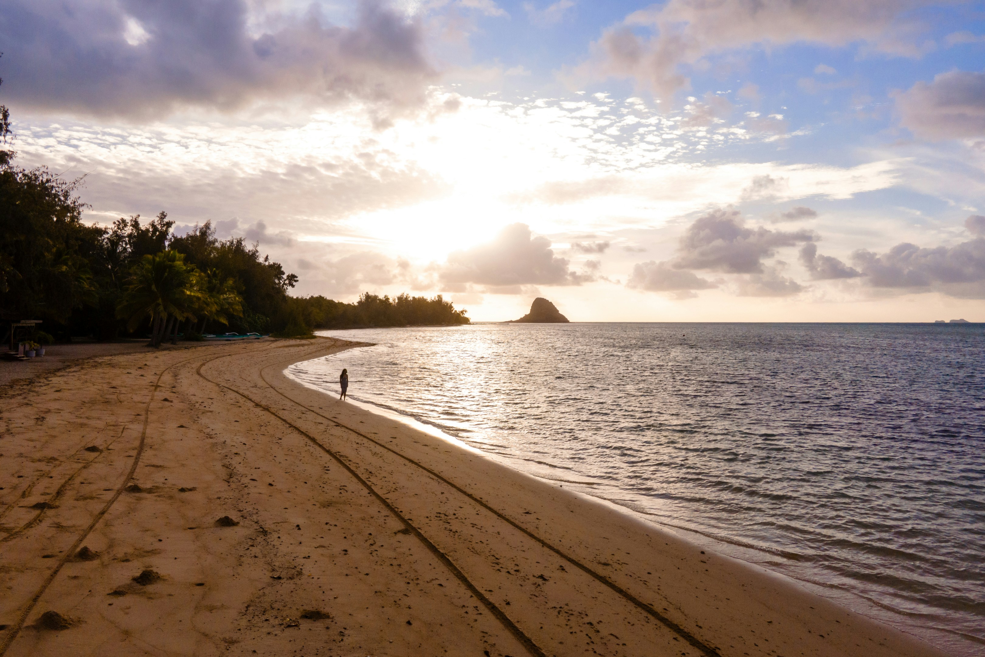 Shoreline Echoes: A Lone Walker at Dusk by the Island's Silhouette