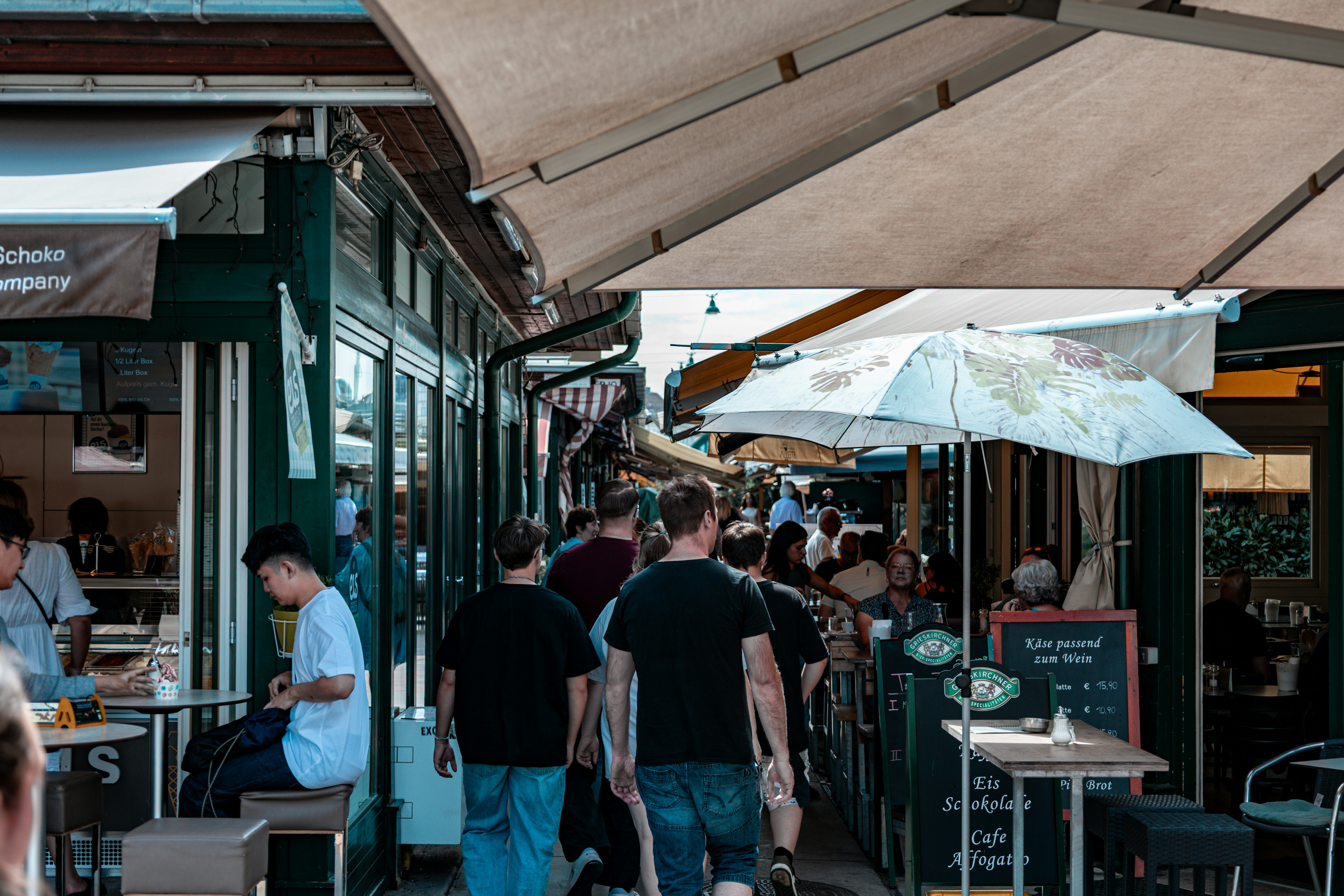 People walk past outdoor cafes in a european town.