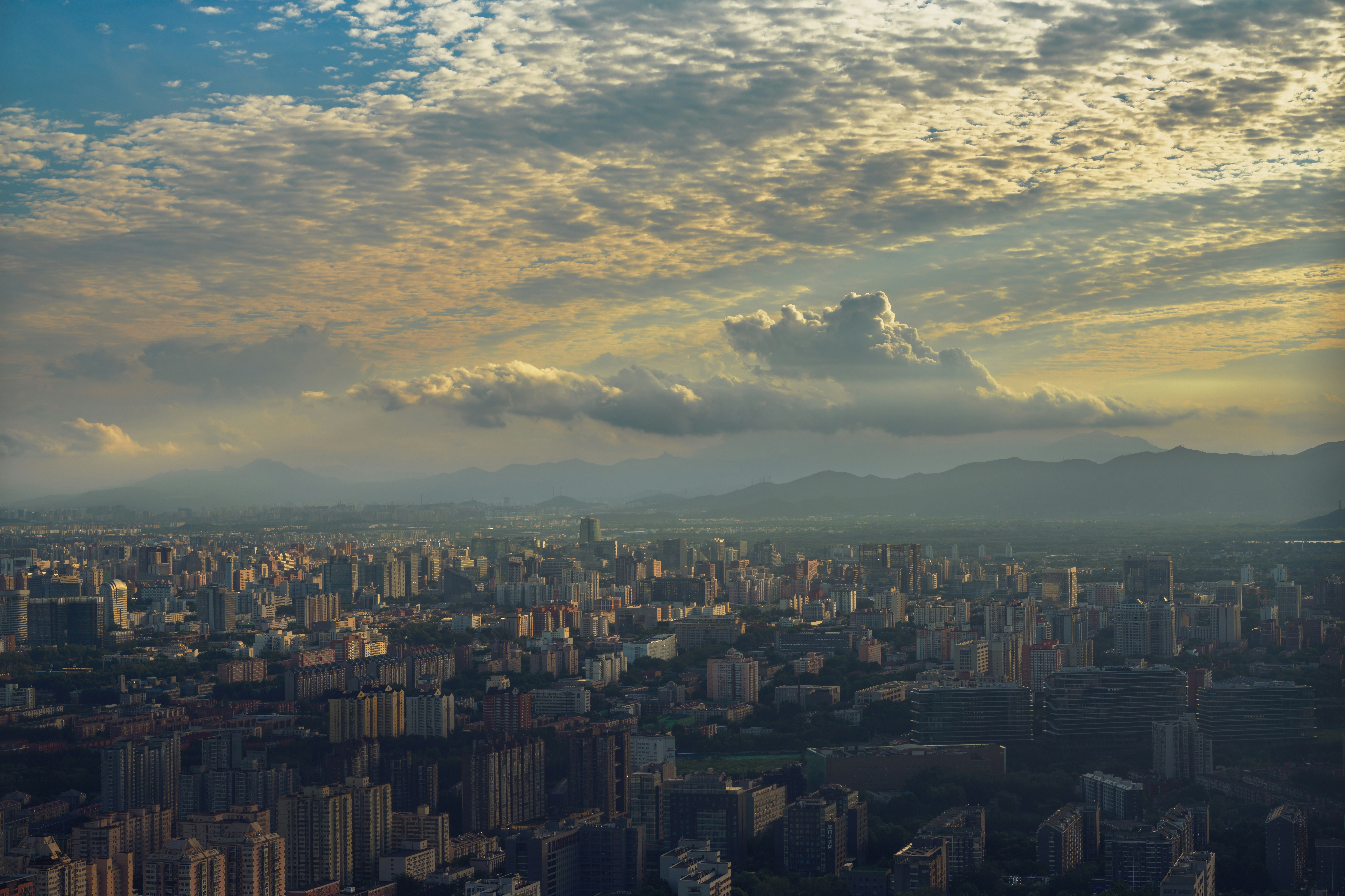 Cityscape under a dramatic, cloudy sky at dusk.