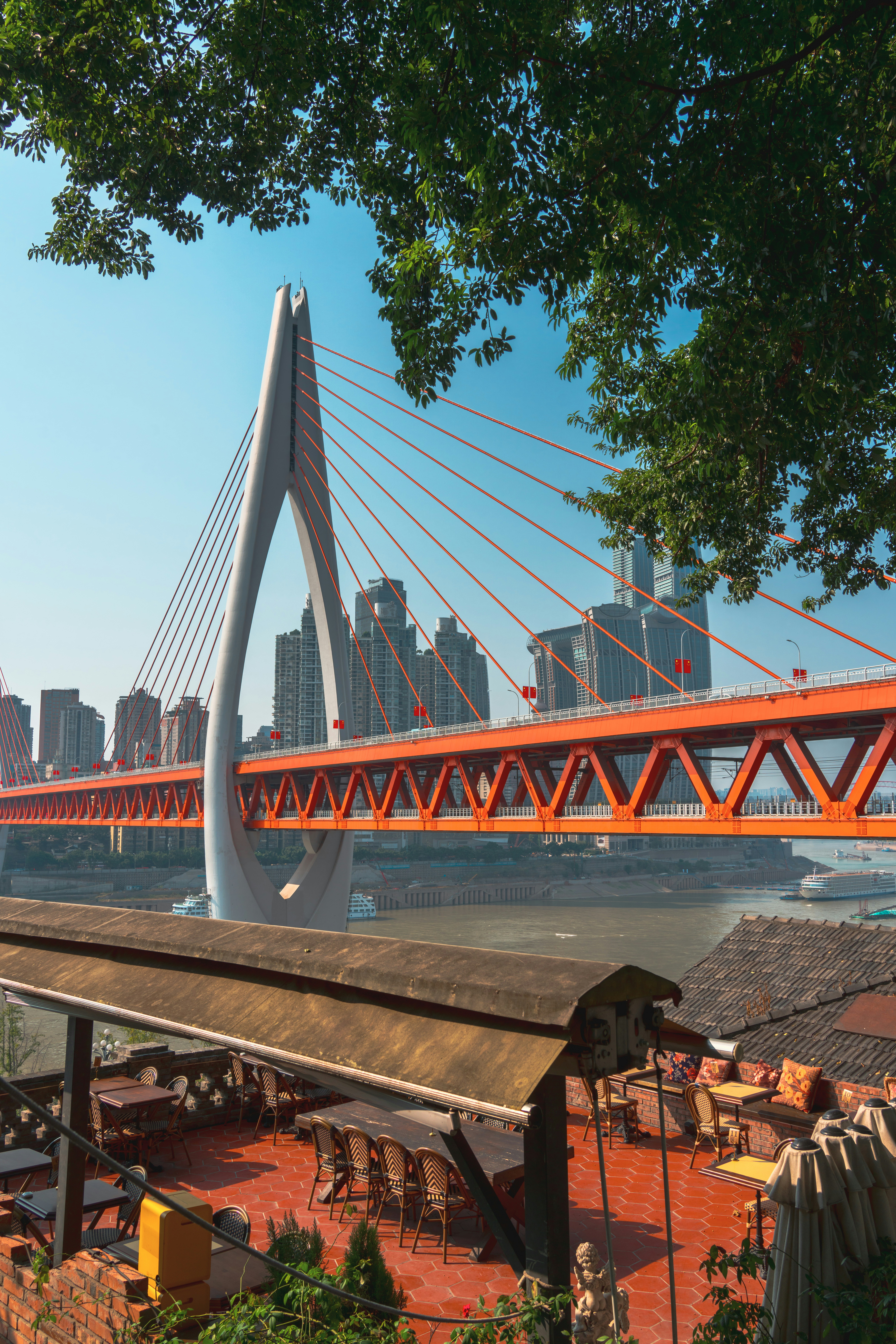 A modern orange bridge spans across a river.