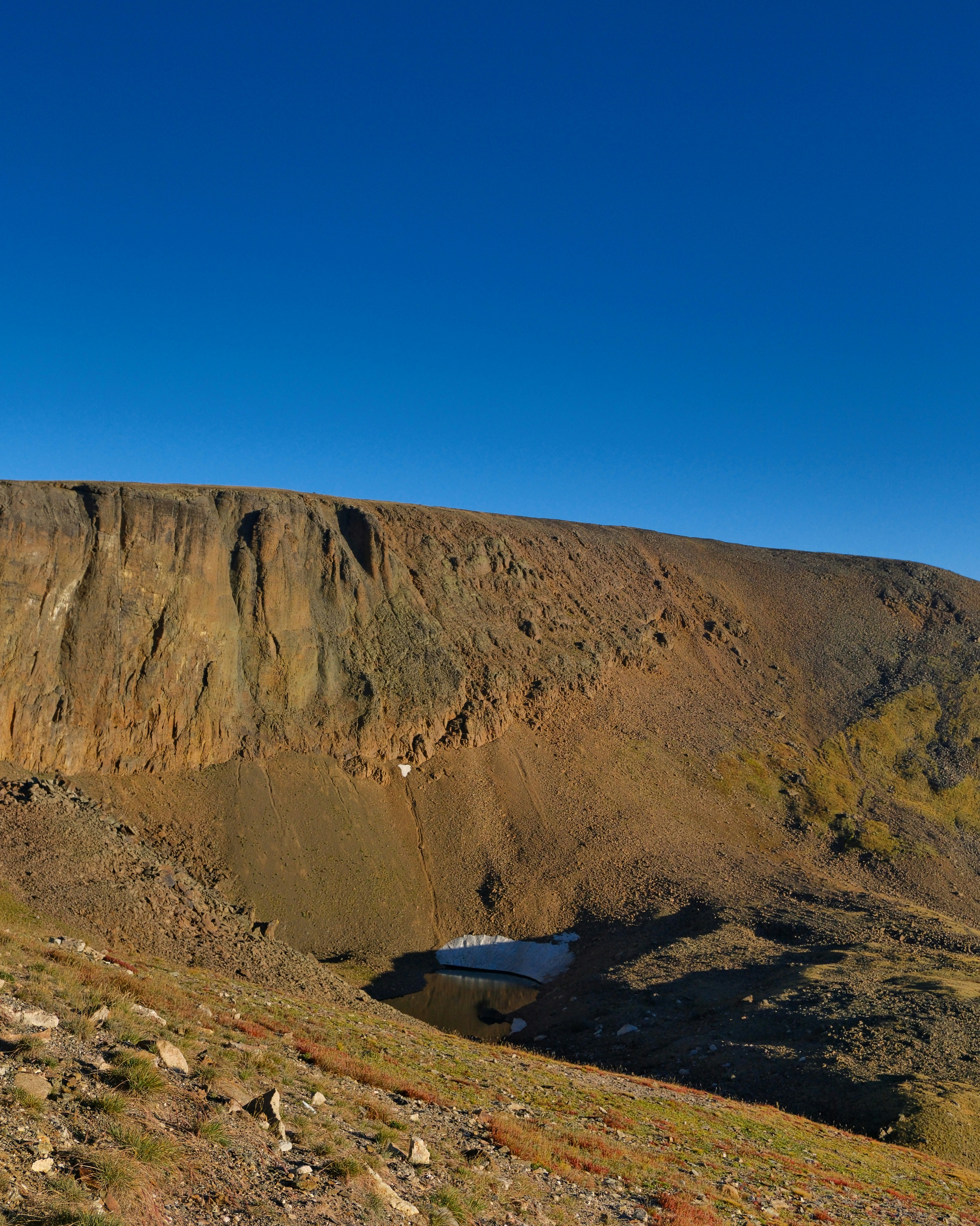 Mountainside against a bright blue sky.