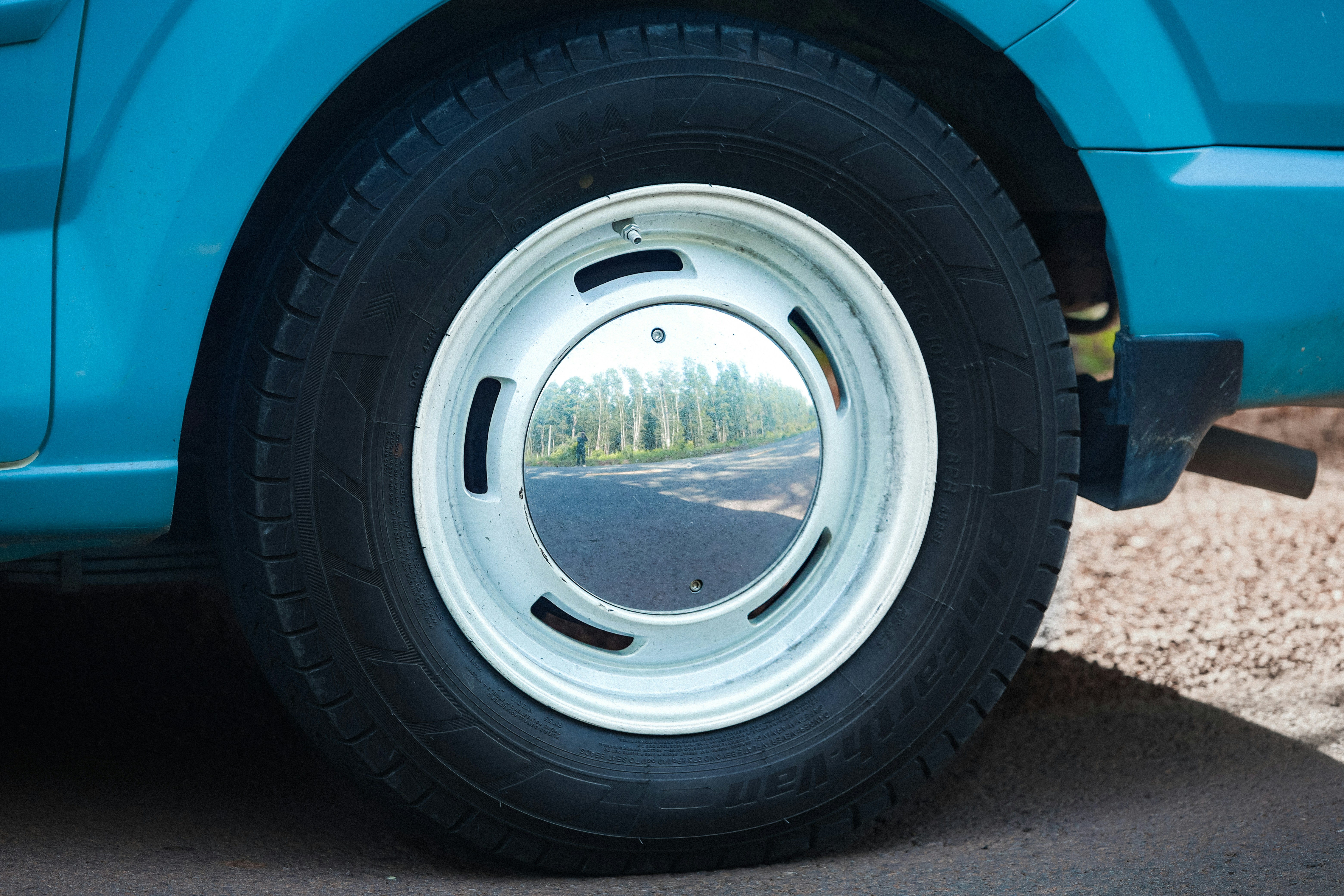 A car wheel and tire reflected in the hubcap.