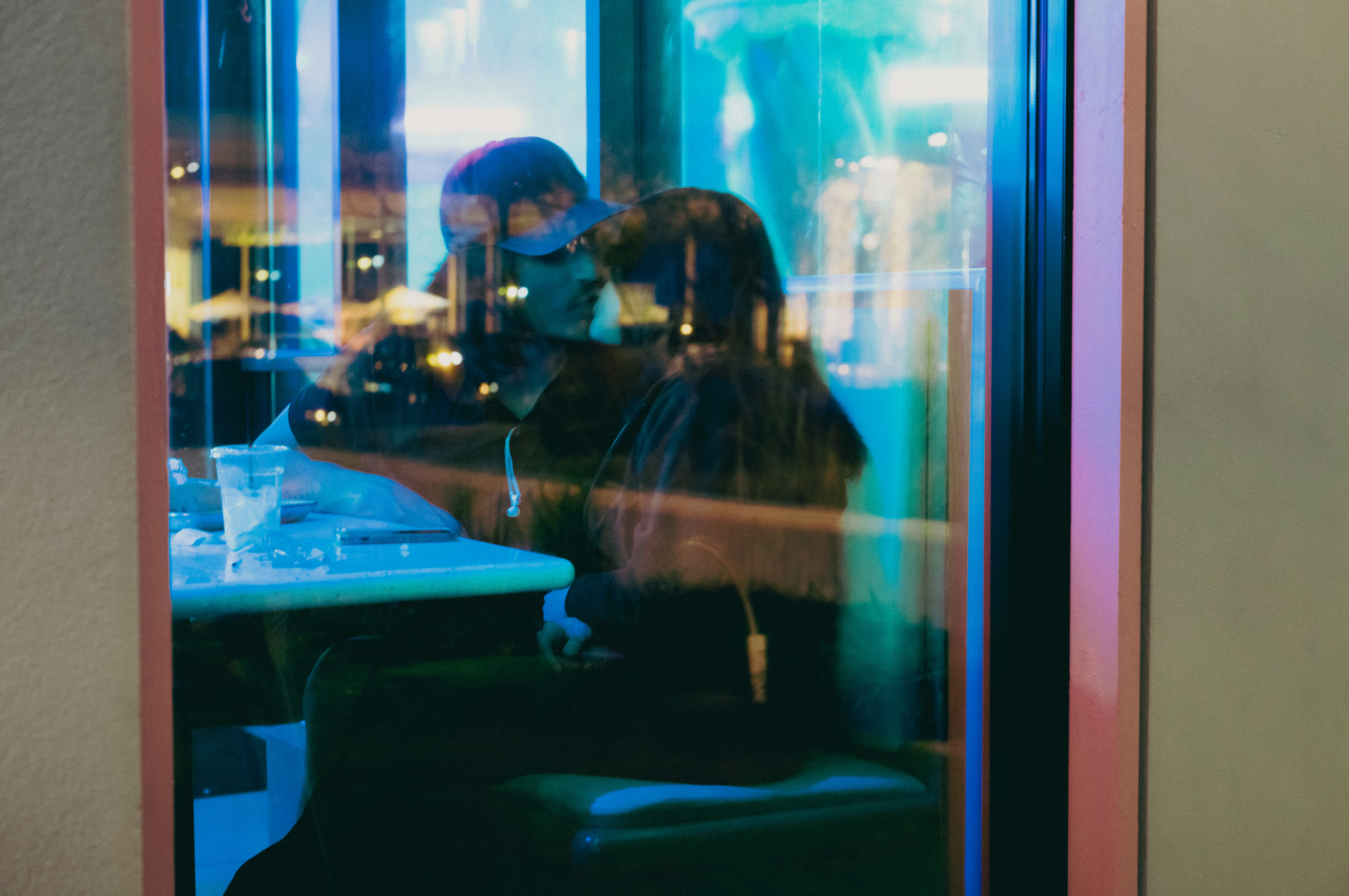 People dine in a restaurant, reflected in glass.