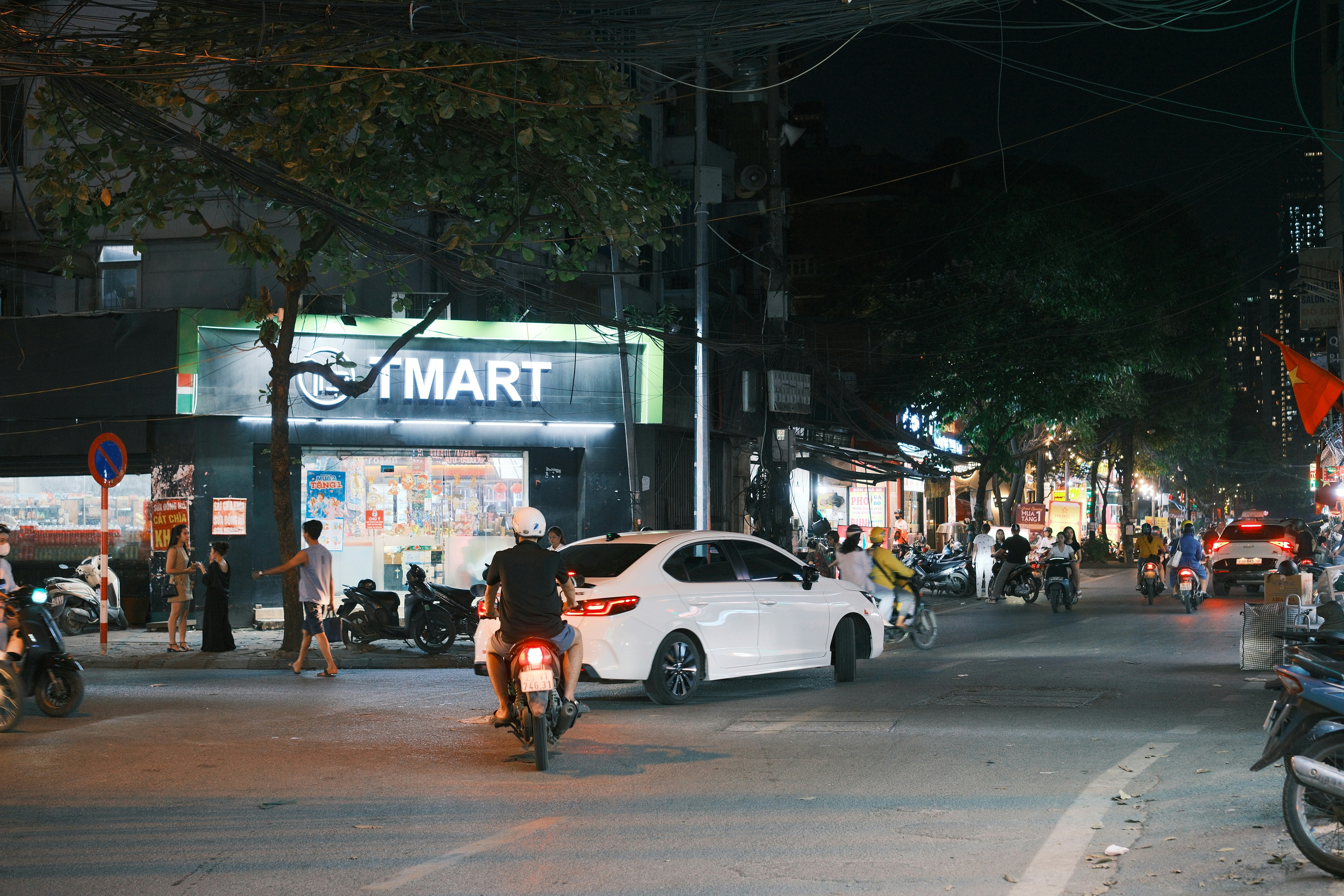 Nighttime scene of a busy street with people and vehicles.