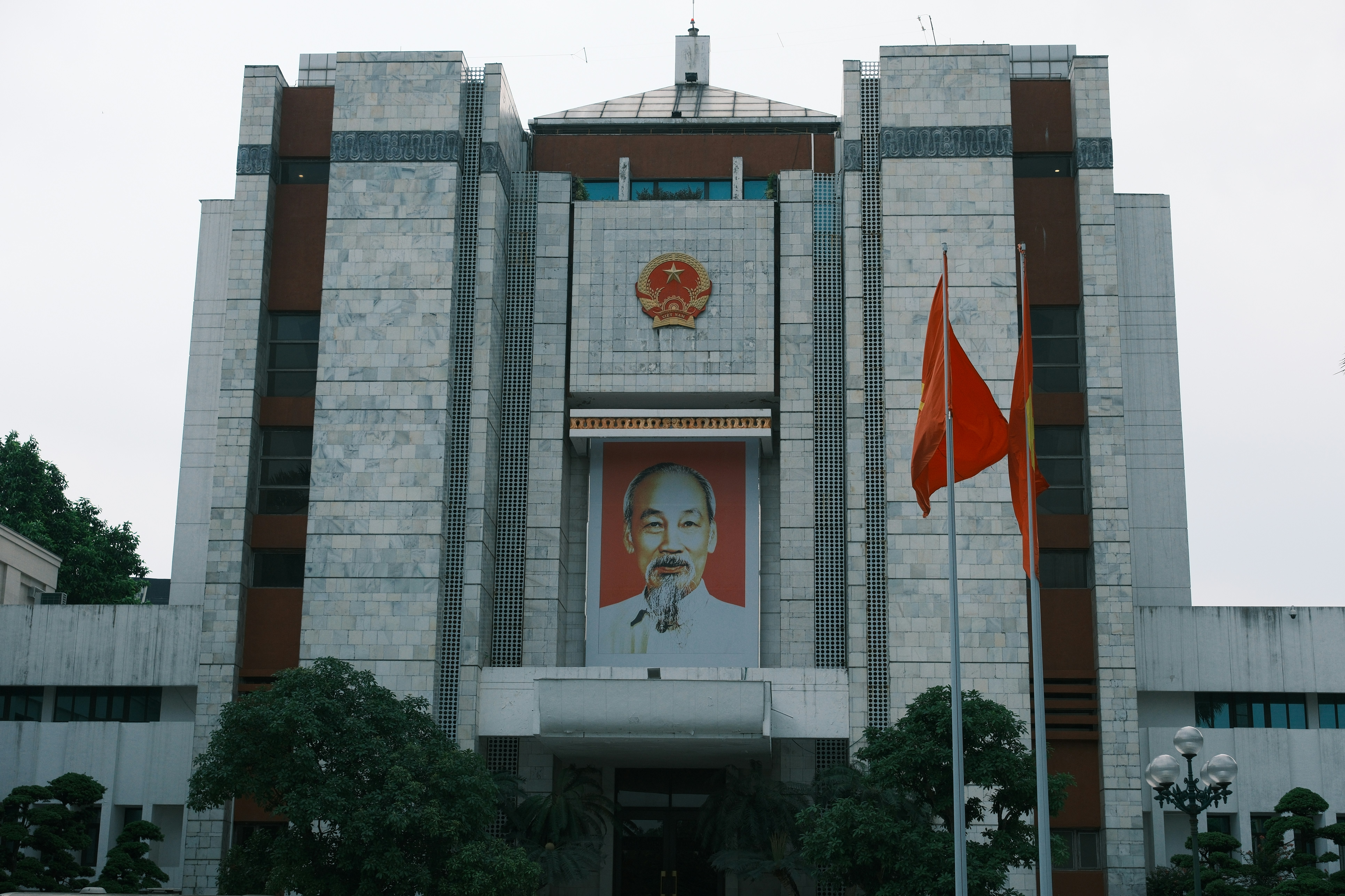 A government building features vietnamese flags and a portrait.