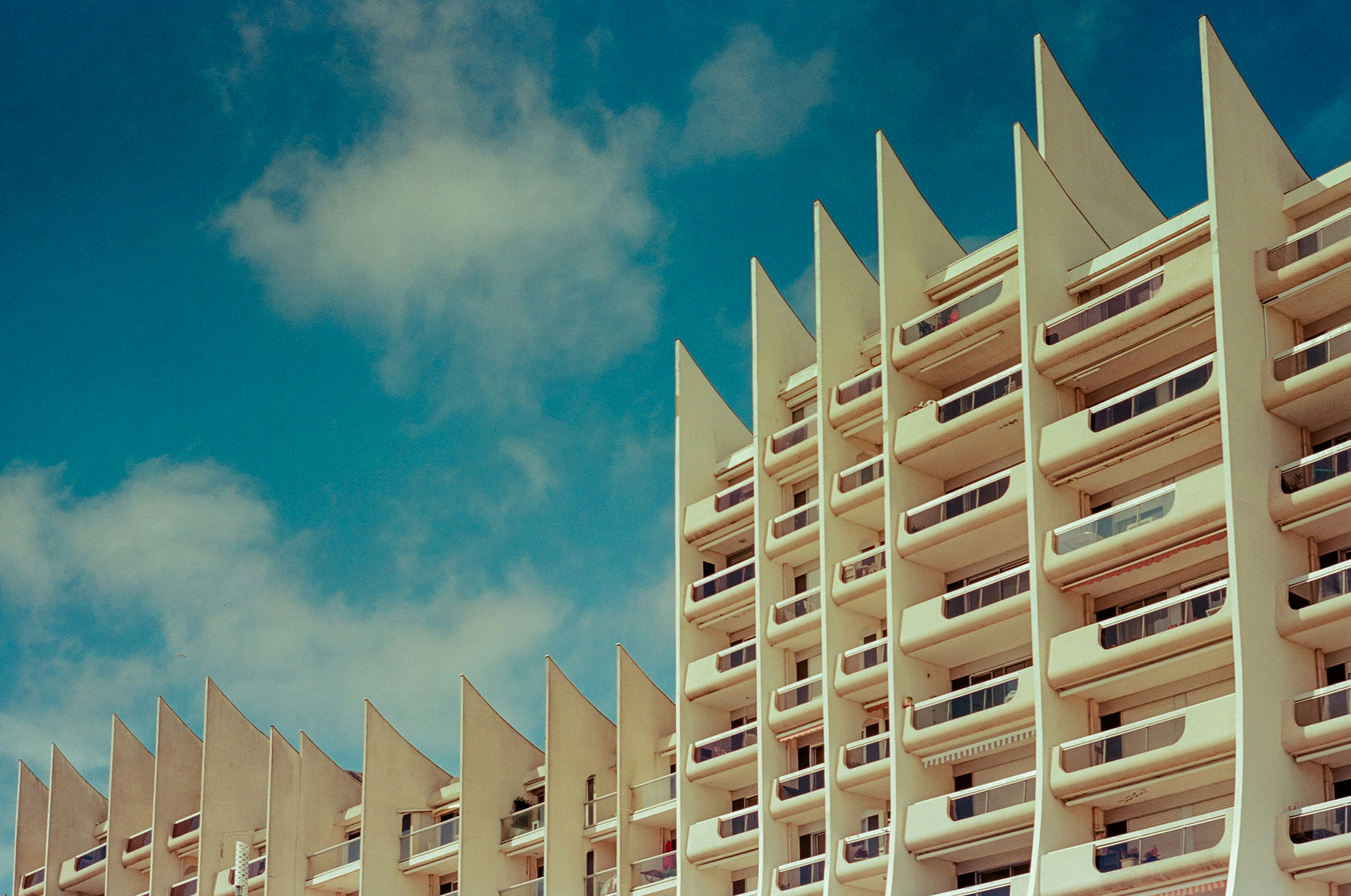 Residential building nicknamed “Les Vagues” in La Baule, France. Captured on Kodak Portra 160 film with a Leica M3 rangefinder camera. The curved, wave-like balconies reflect the seaside atmosphere of this elegant Atlantic resort town. | Modern apartment building against a bright blue sky.