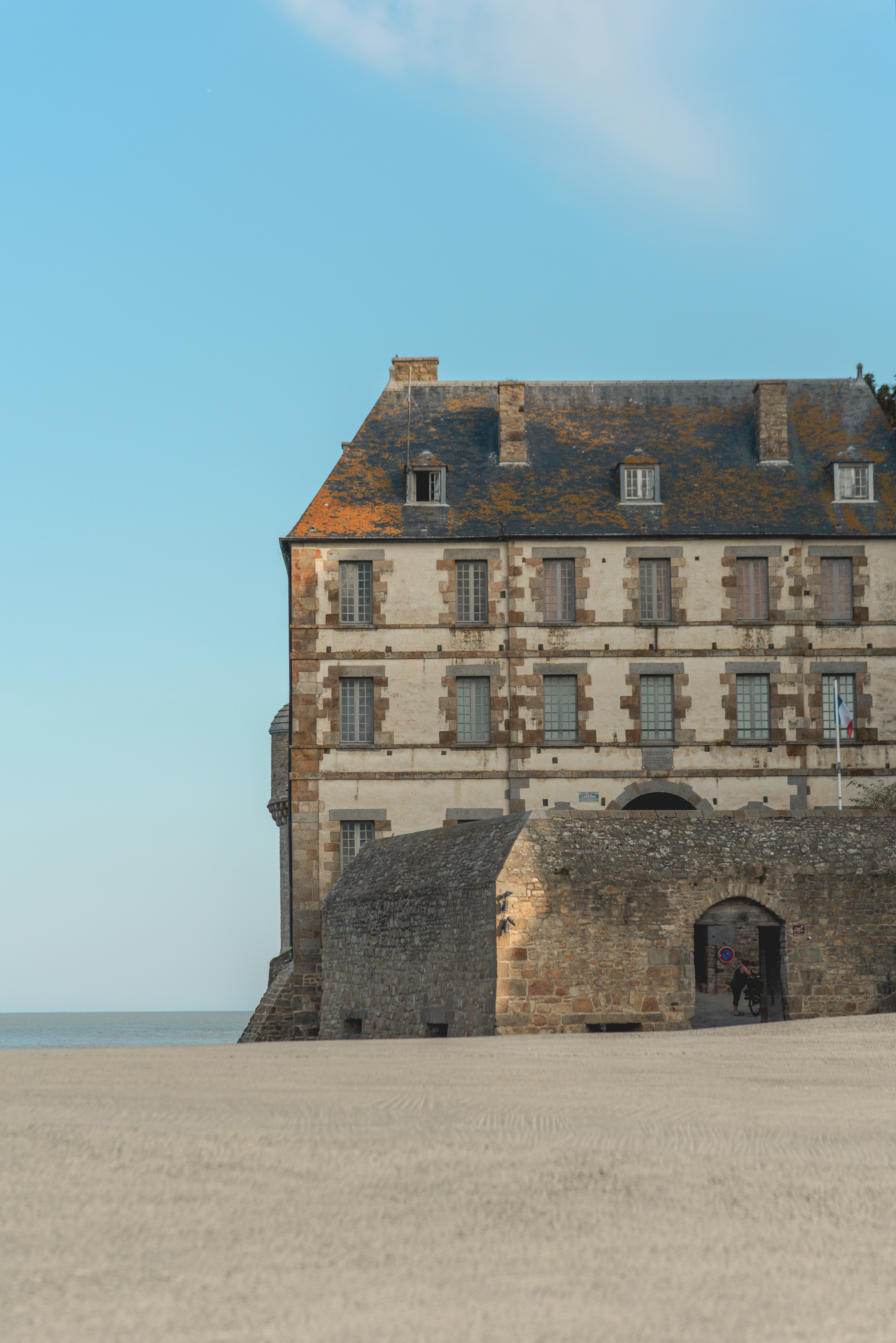 An ancient stone building faces the sea.