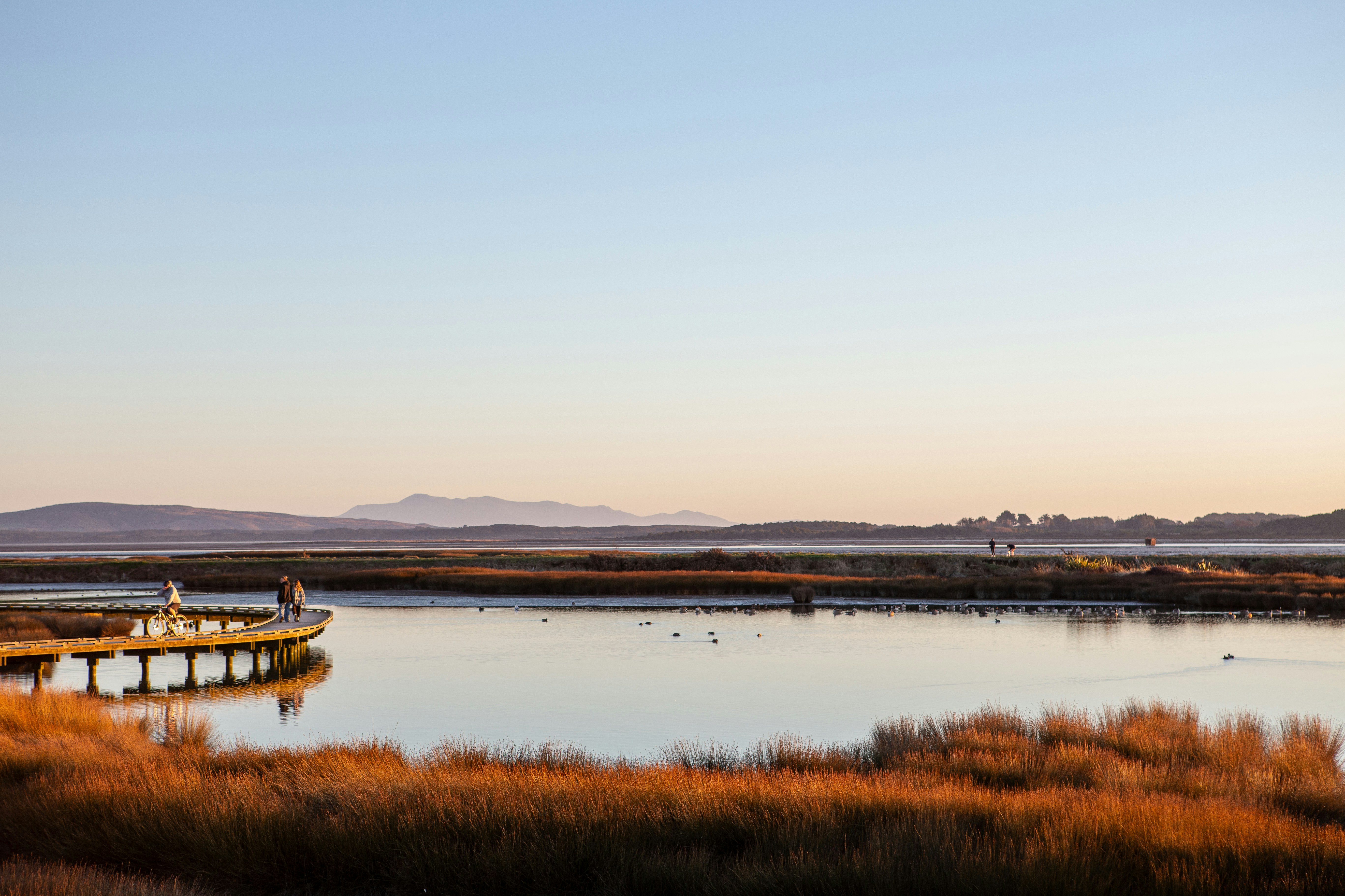 A wooden pier overlooks a serene lake at sunset.