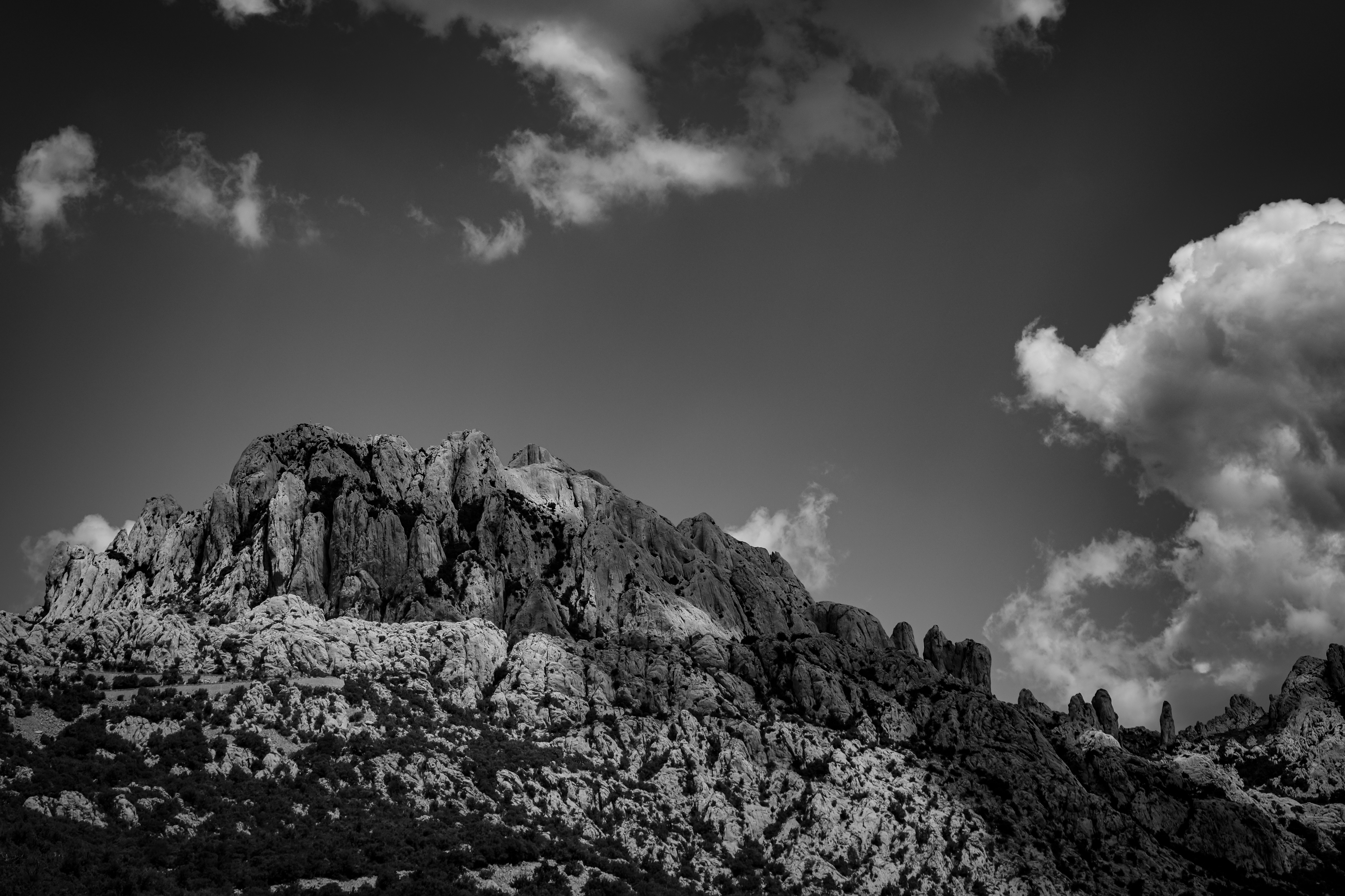 Mountains loom beneath a cloudy sky in black and white.