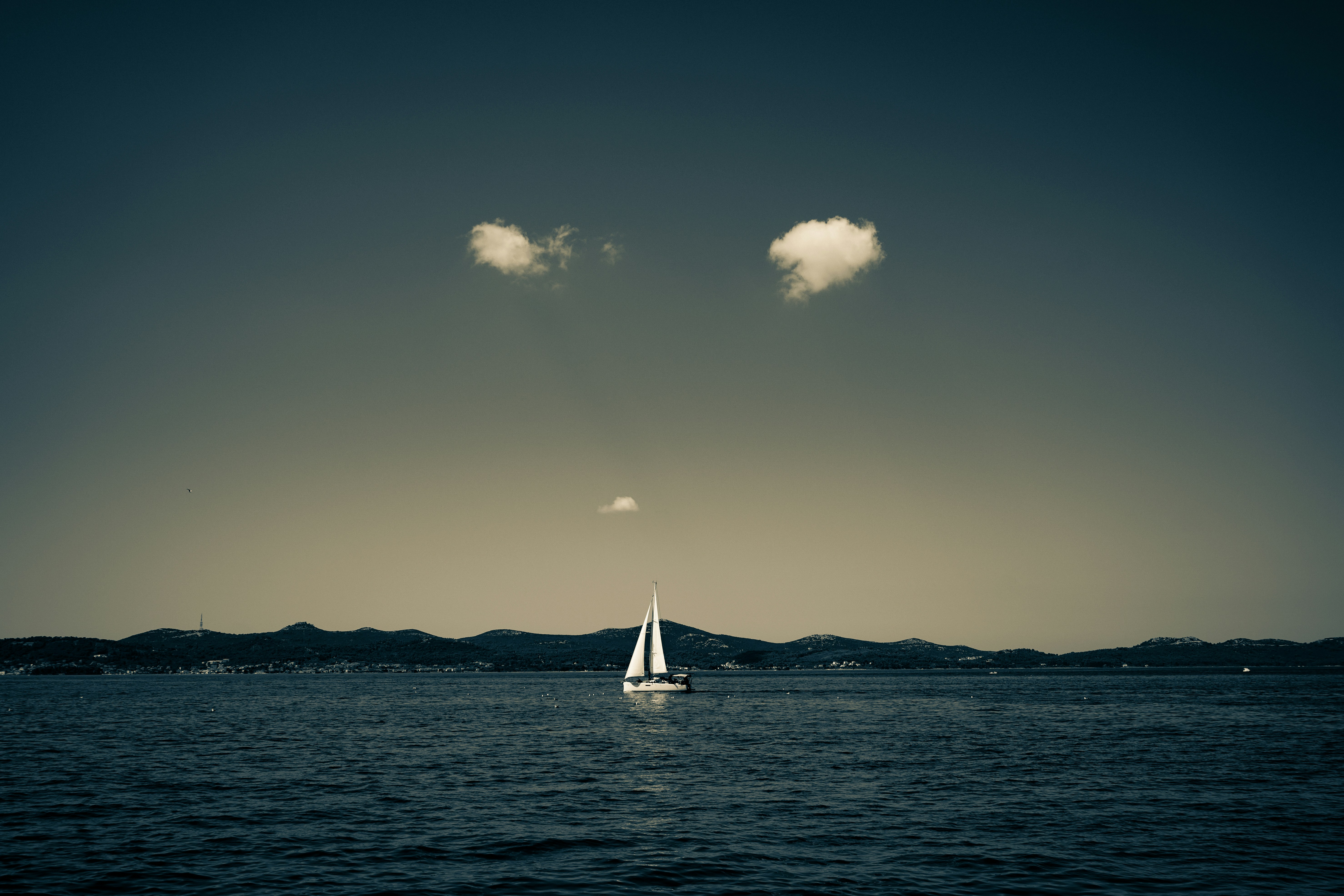 Sailboat sailing on a dark, vast sea.
