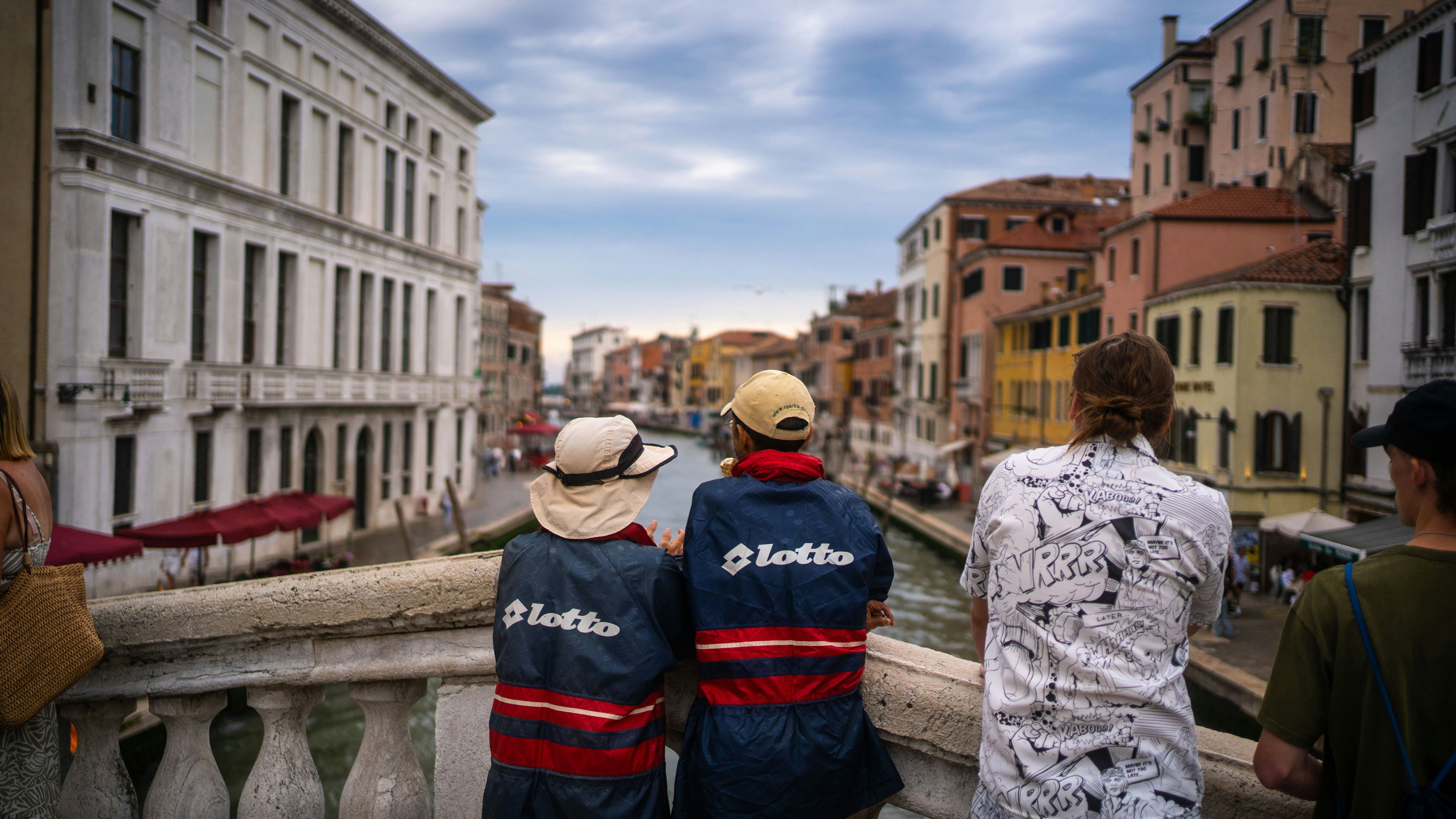 Man & Woman standing in Venice with vintage lotto Clothing | People admire a scenic canal view in venice.