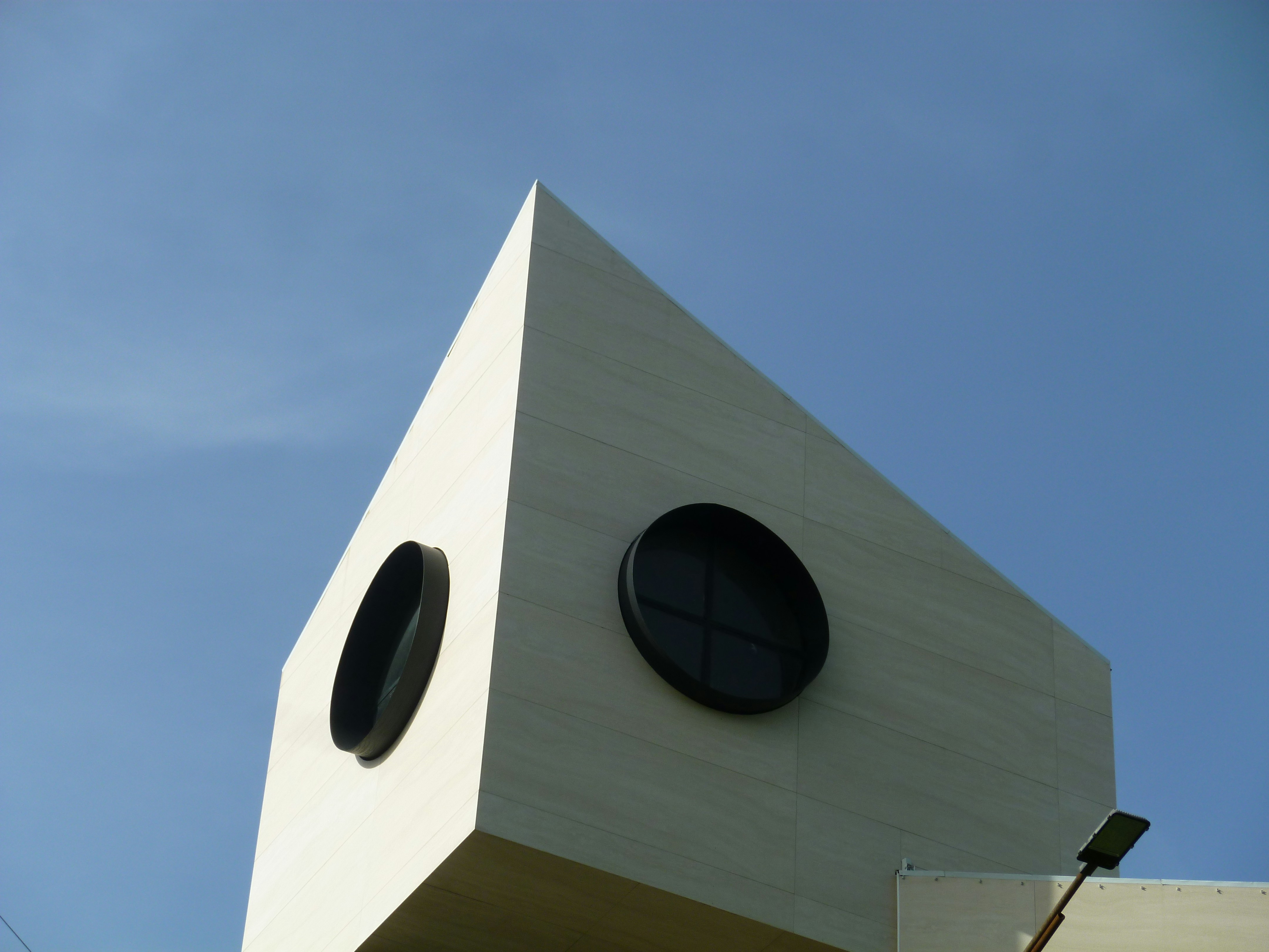 Modern building with circular windows against blue sky.