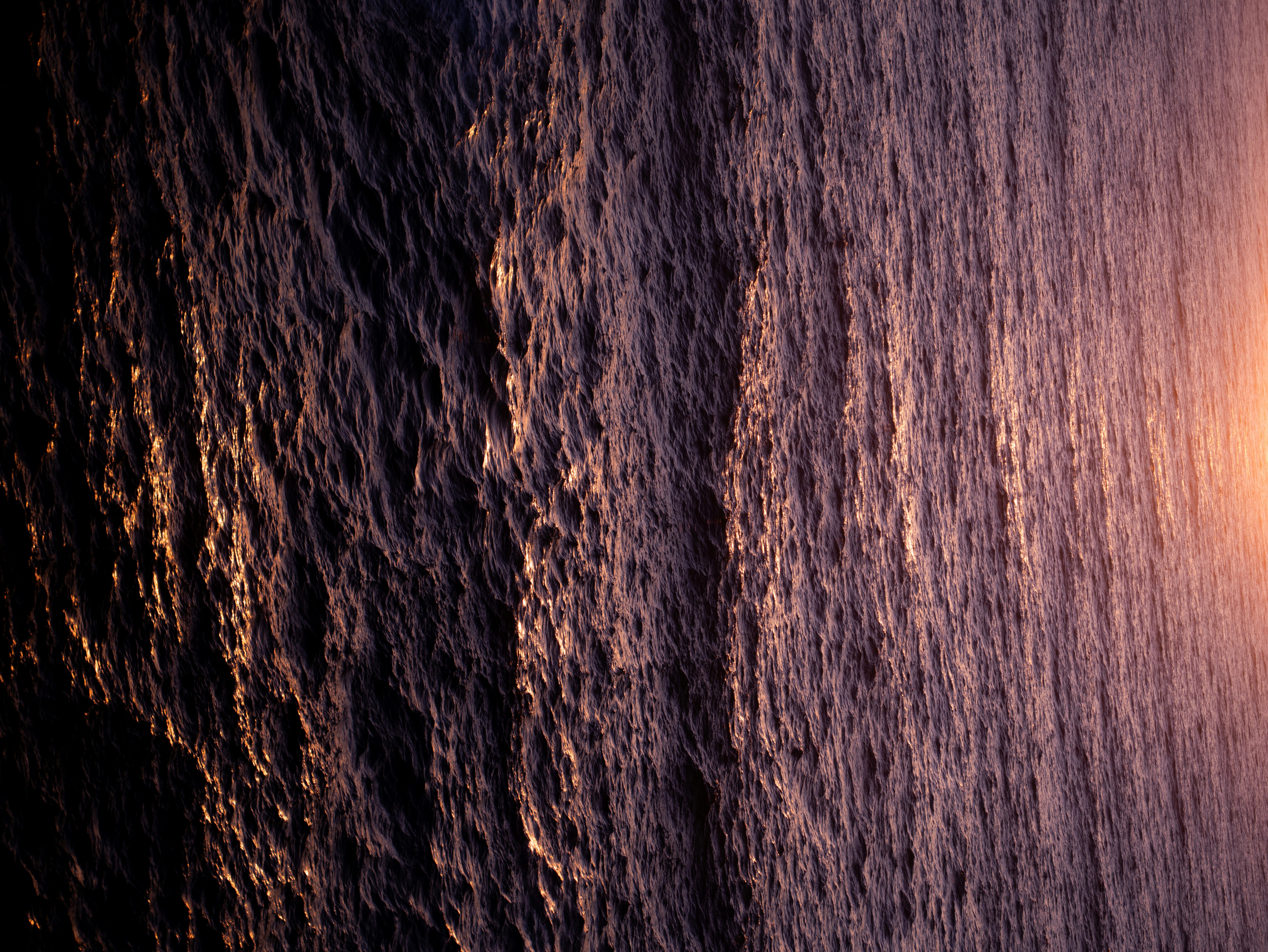 Glistening ocean waves reflect the hues of a setting sun, creating a serene atmosphere. The interplay of light and water captures the tranquility of dusk.