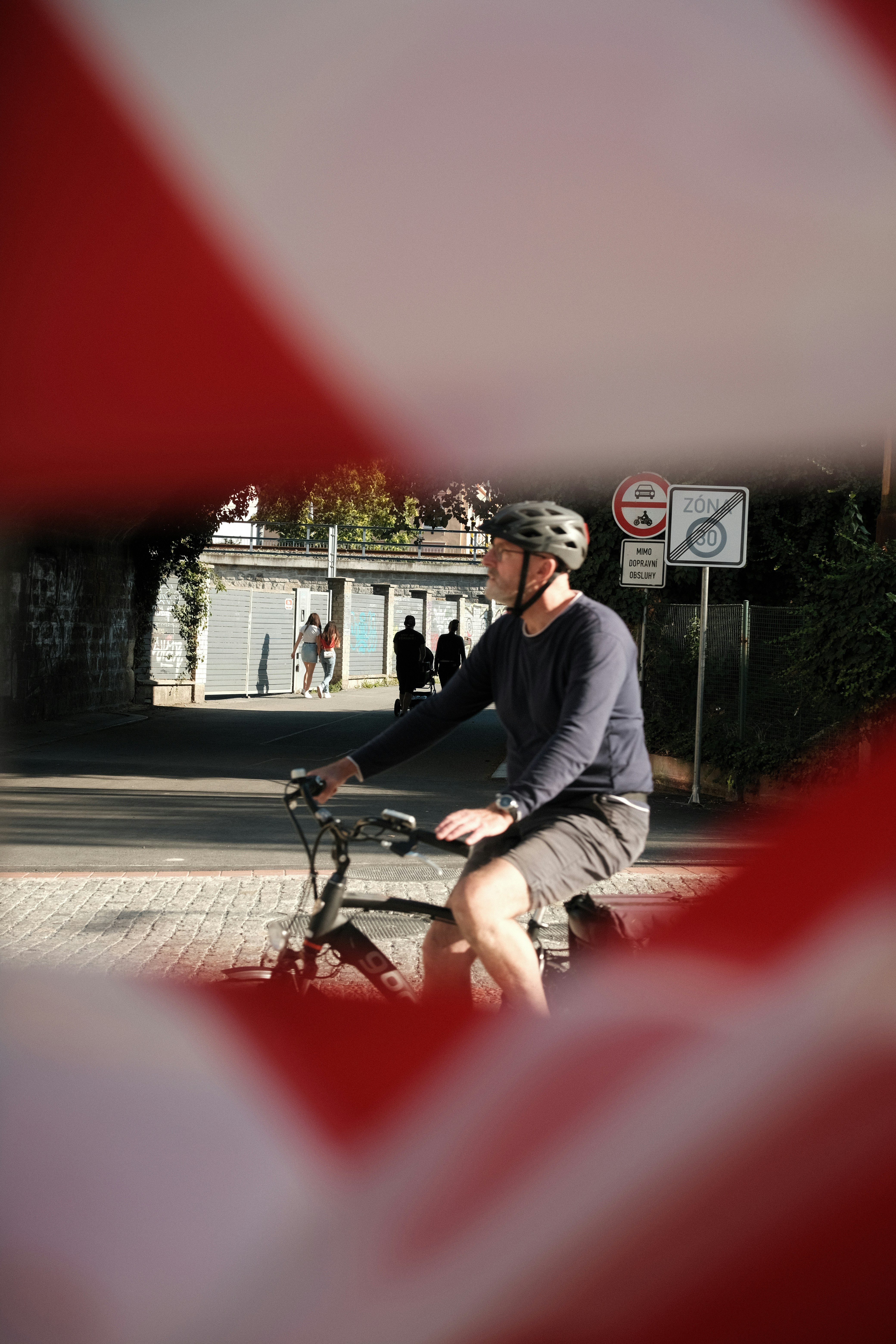 Bicyclist riding on street behind a barrier | A cyclist rides down a street.