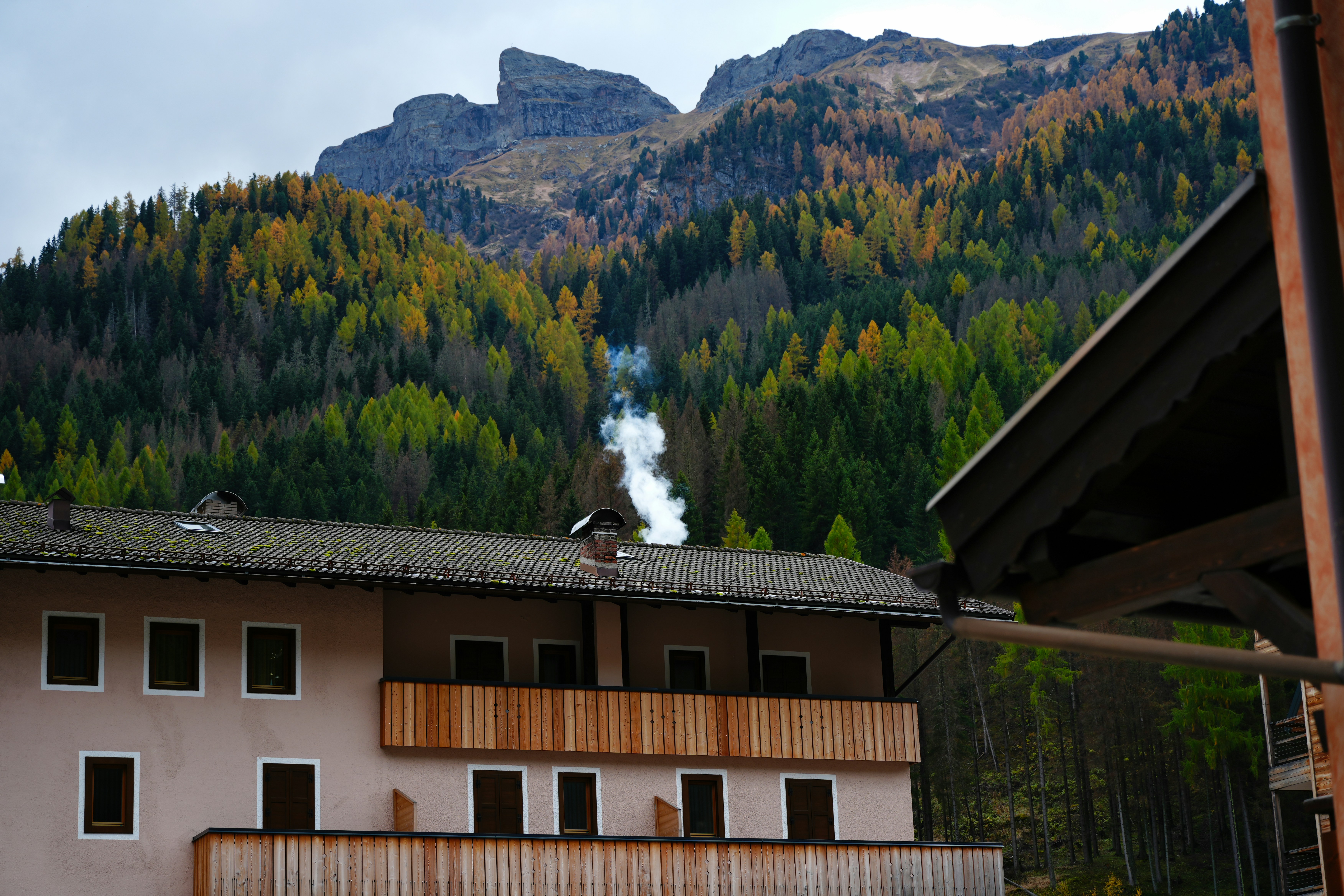 Smoke rises from a building near the mountains.