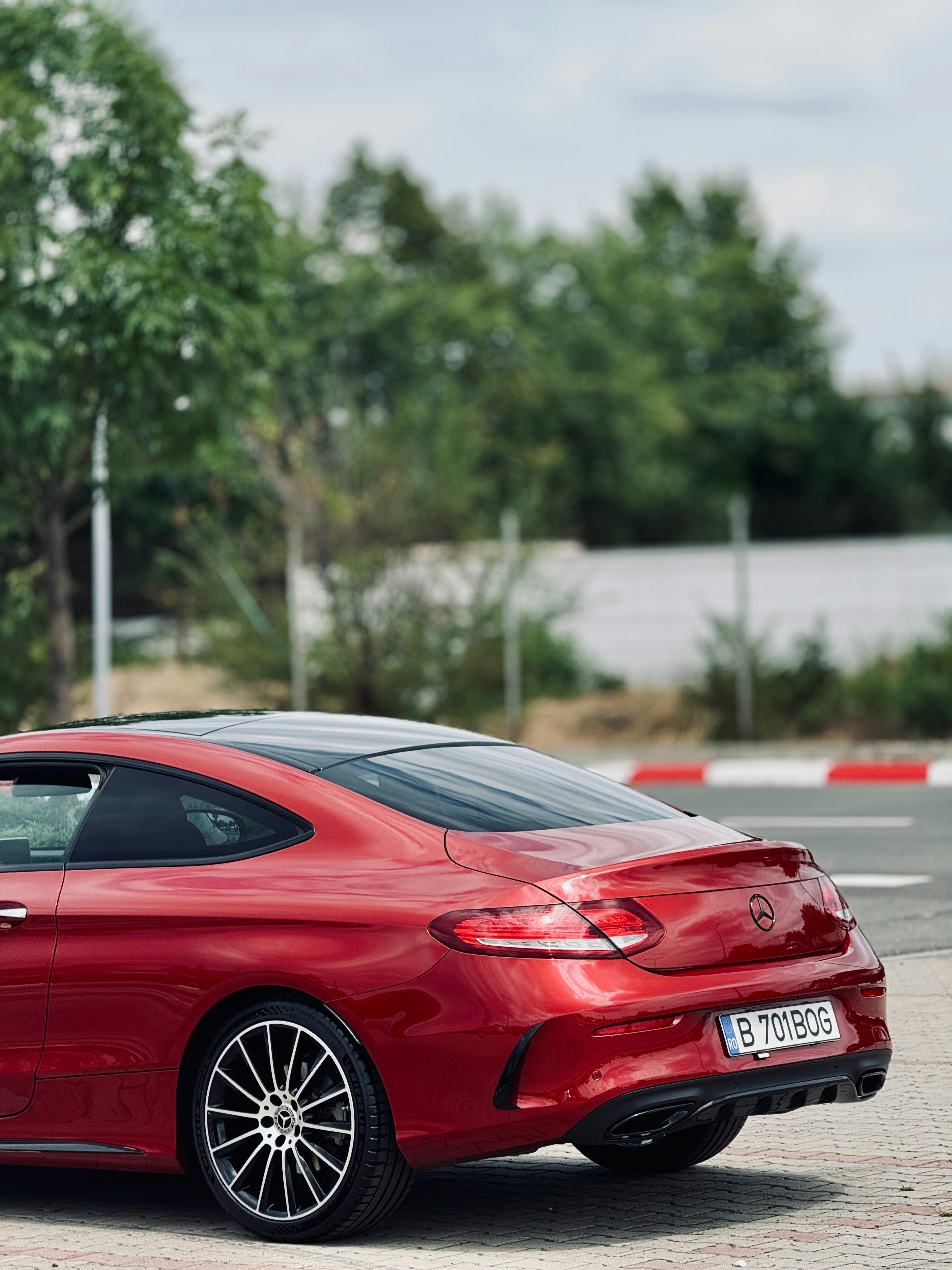 Sleek red Mercedes coupe parked against a blurred urban backdrop, showcasing its elegant curves and modern design.